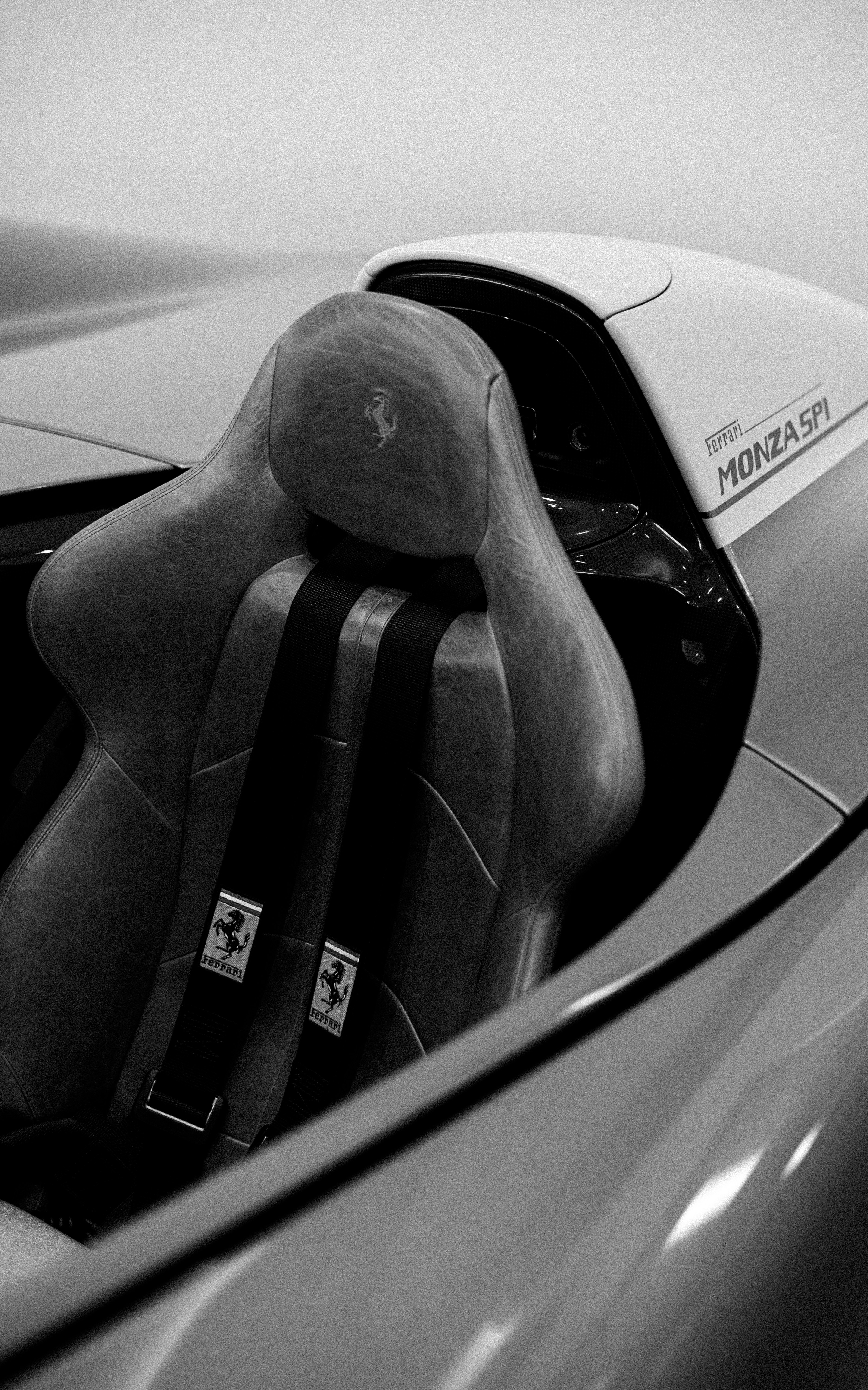 Monochrome photograph of a sleek car interior focusing on a contoured seat and minimalist design.