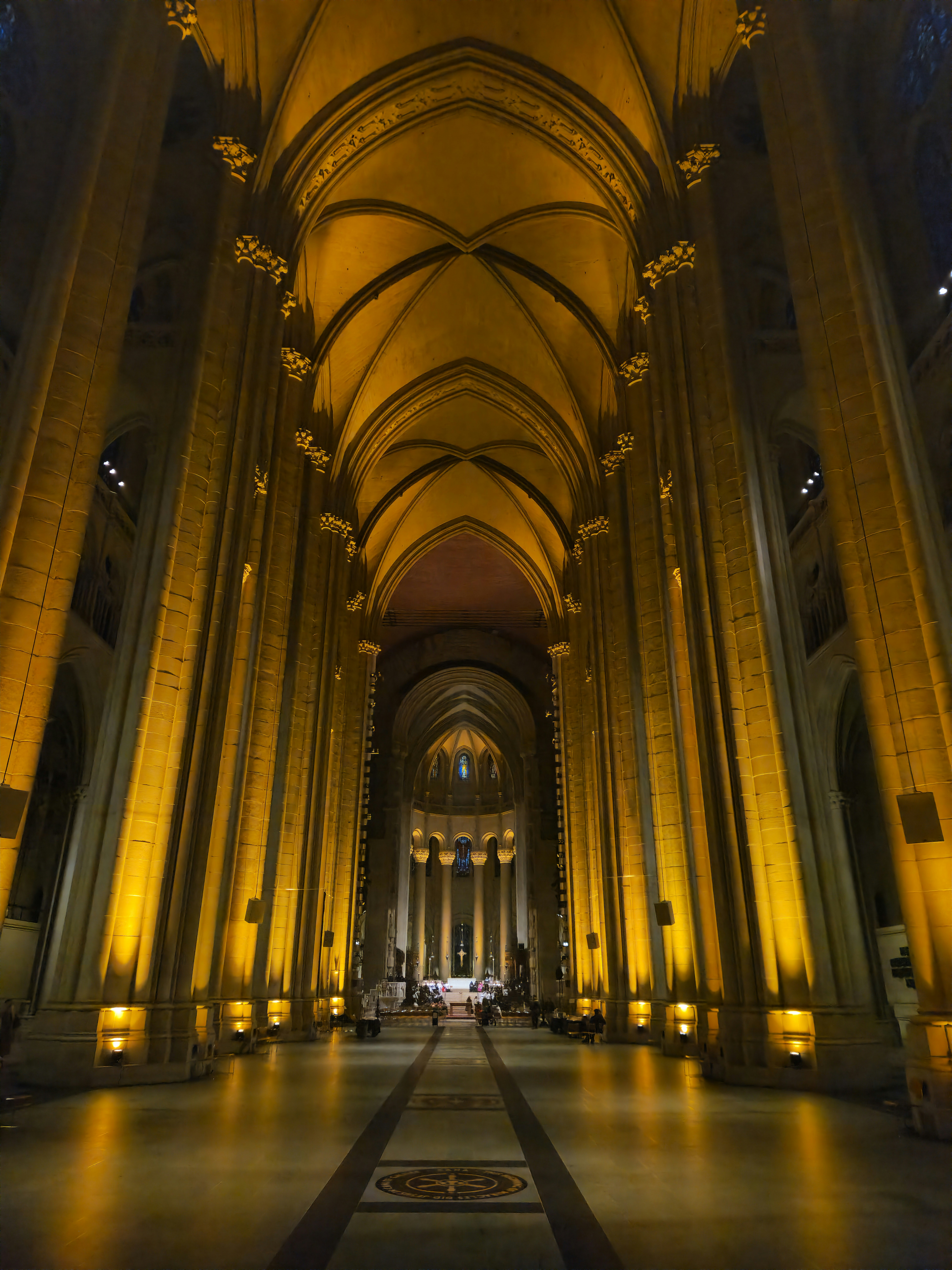 Gothic cathedral interior with towering arches illuminated in warm golden light.