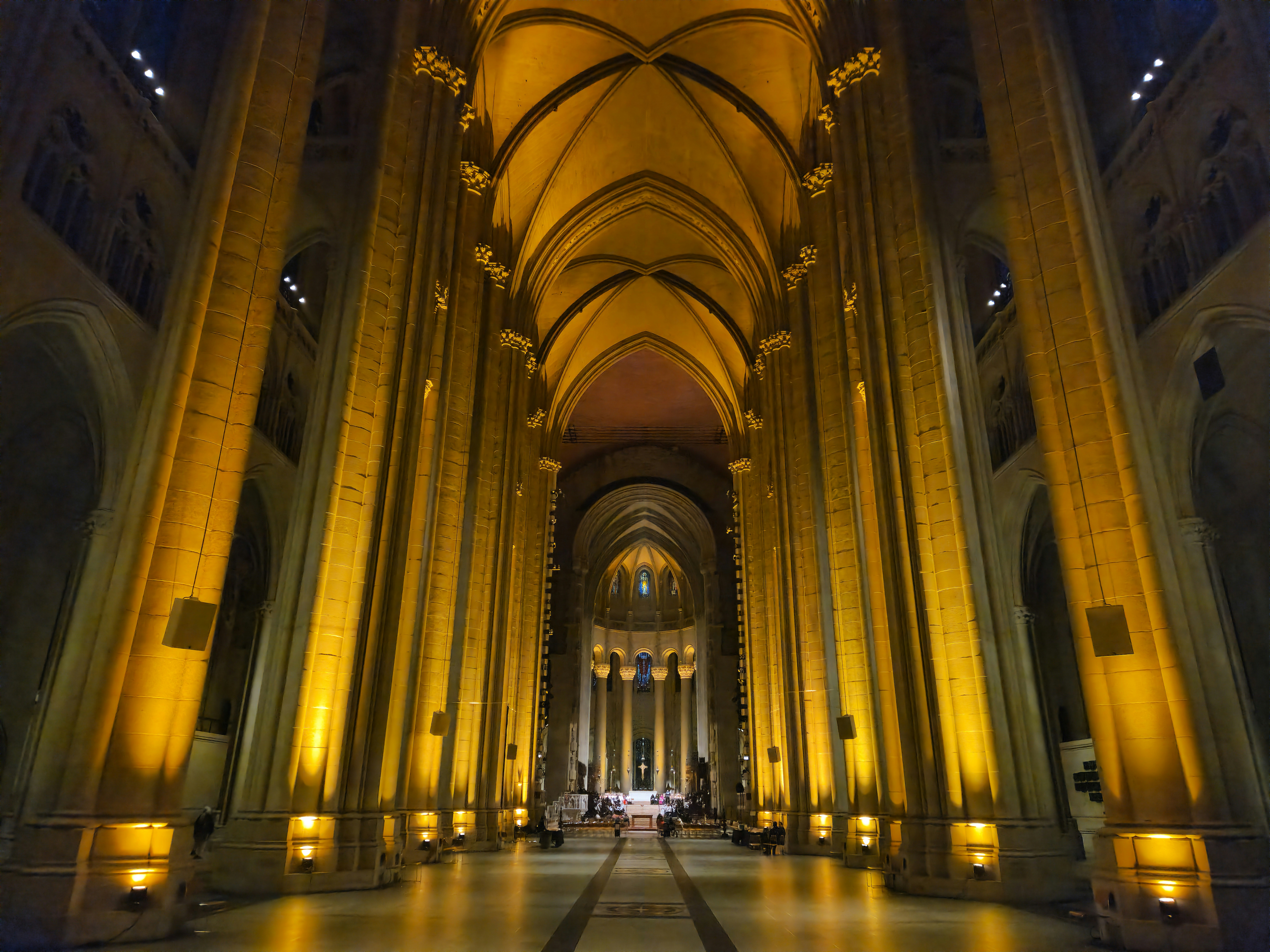Interior of a grand cathedral with towering columns and warm golden lighting.