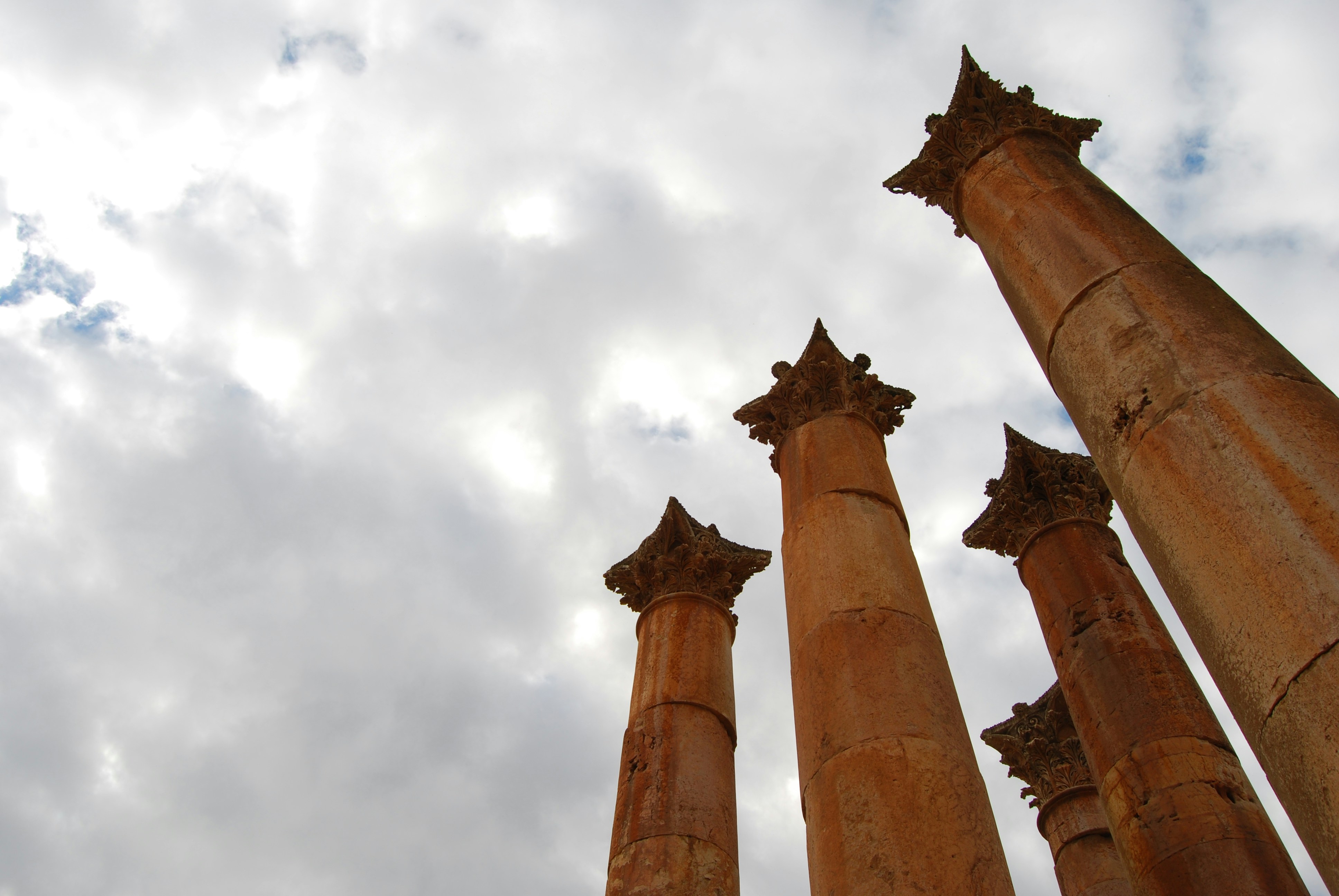Ancient columns rise against a dramatic sky, showcasing intricate details and weathered textures. The scene evokes a sense of history and grandeur.