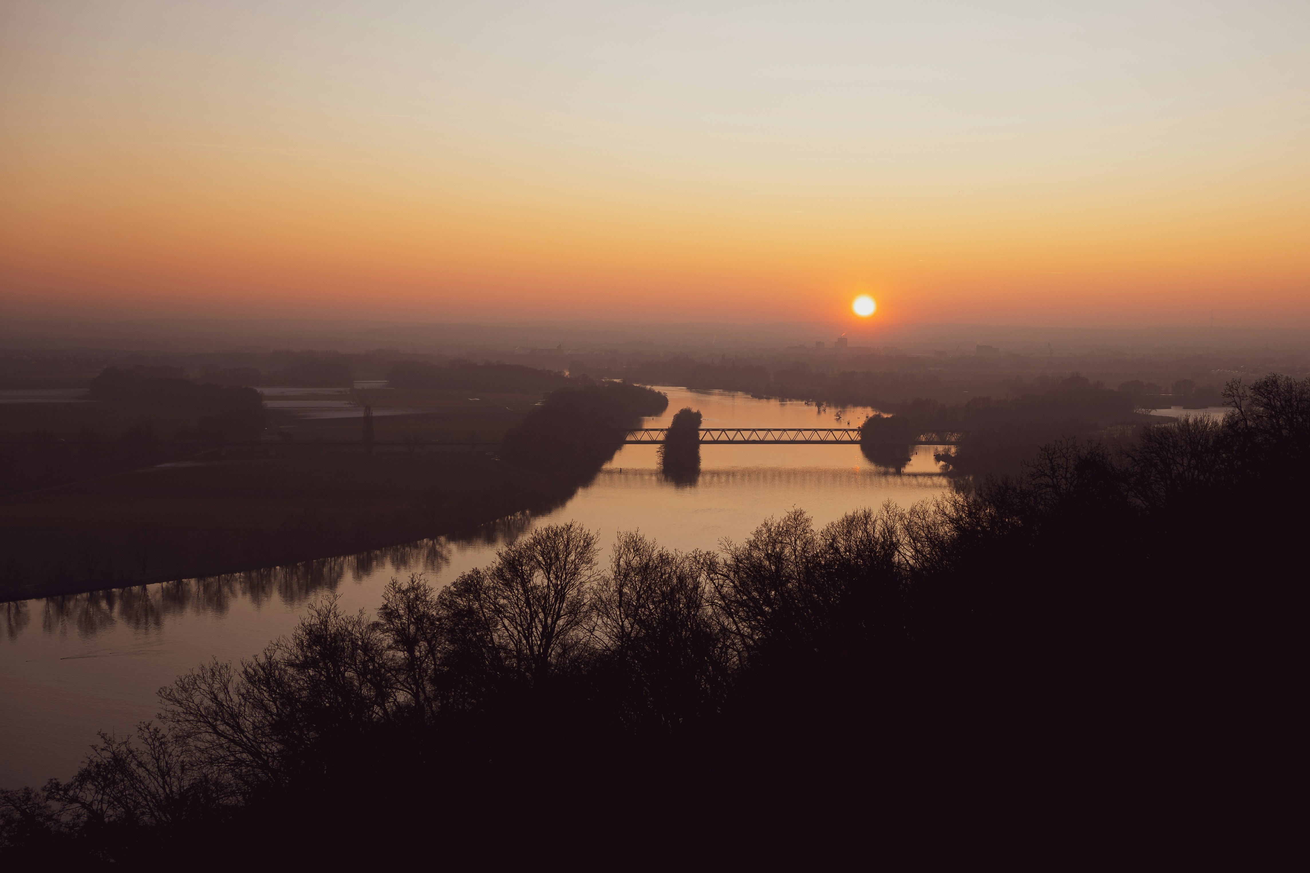 Sunset casting warm hues over a river winding through a tranquil landscape.