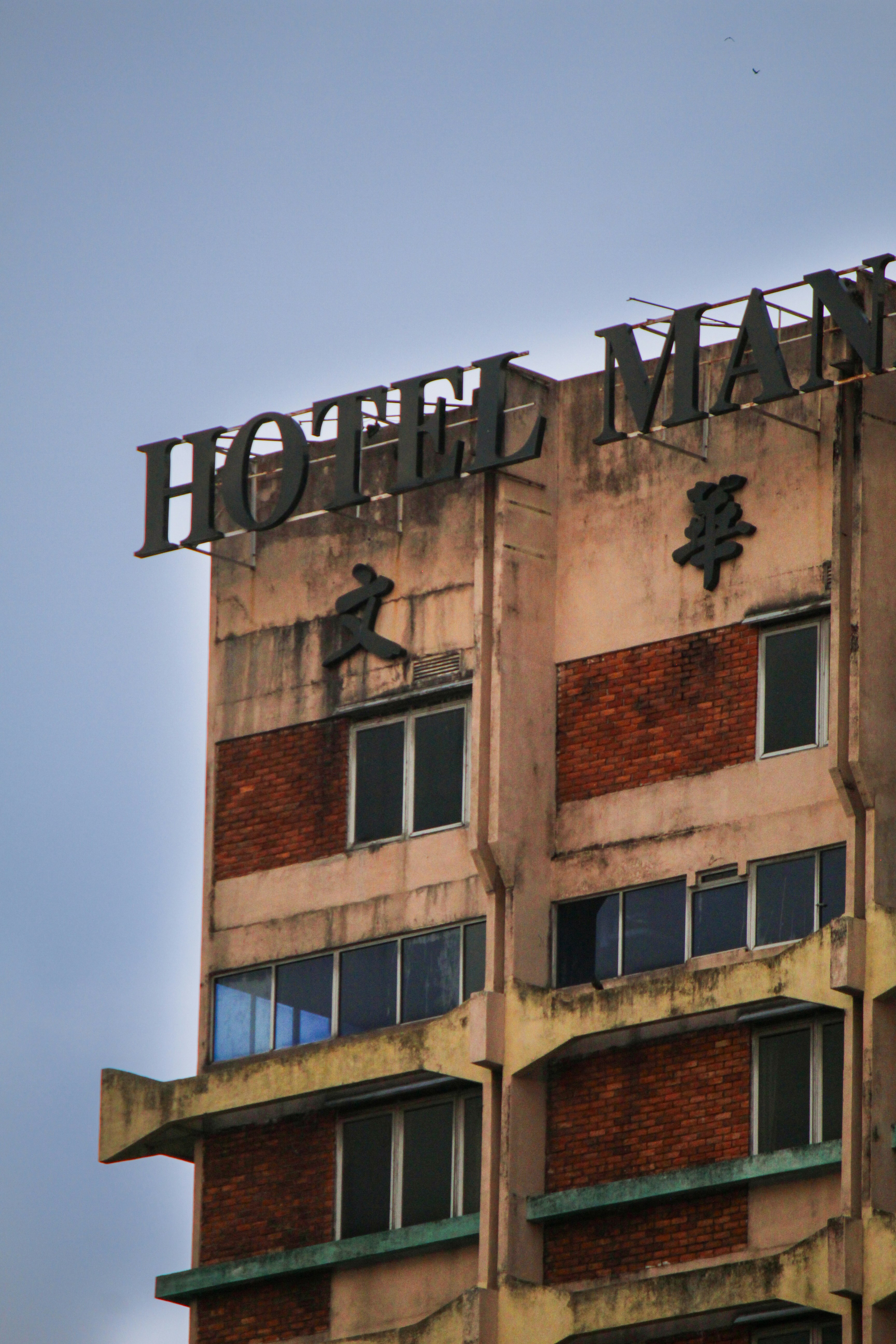Weathered hotel face under a pale blue sky