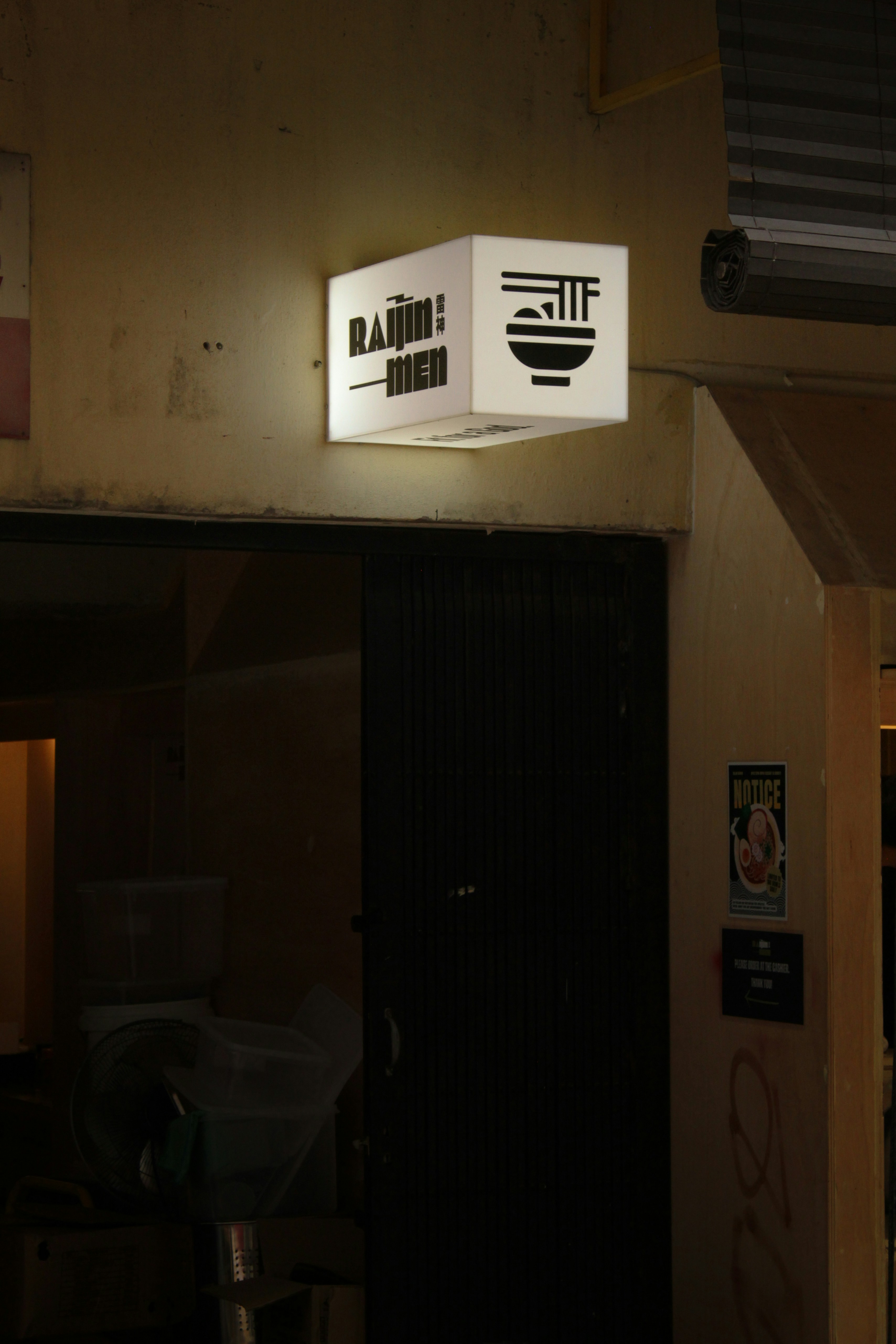 Stylized sign for 'RATIM & MEN' illuminated against a muted background, highlighting urban aesthetics and branding.