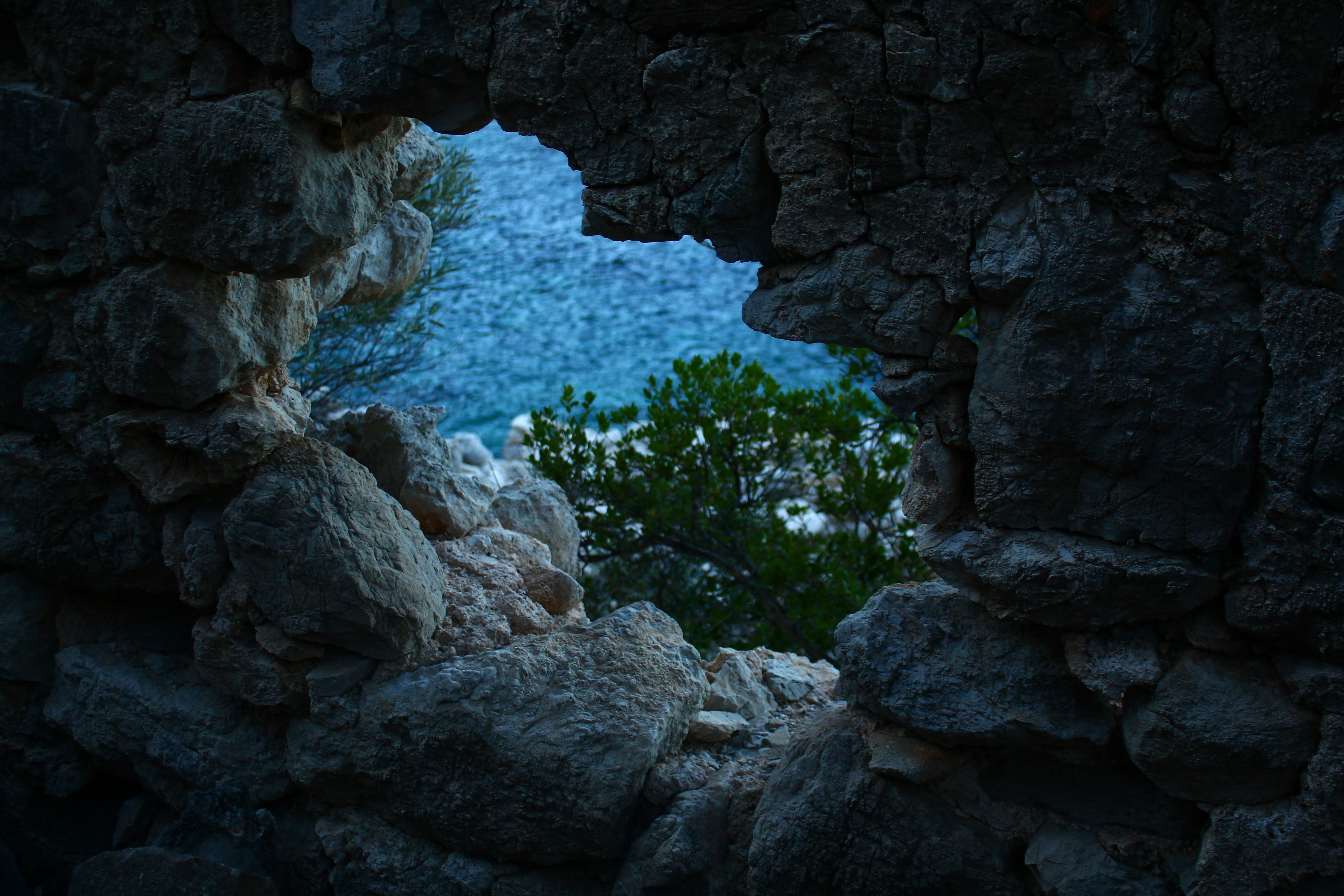 A view of a body of water through a hole in a rock wall photo – Free ...