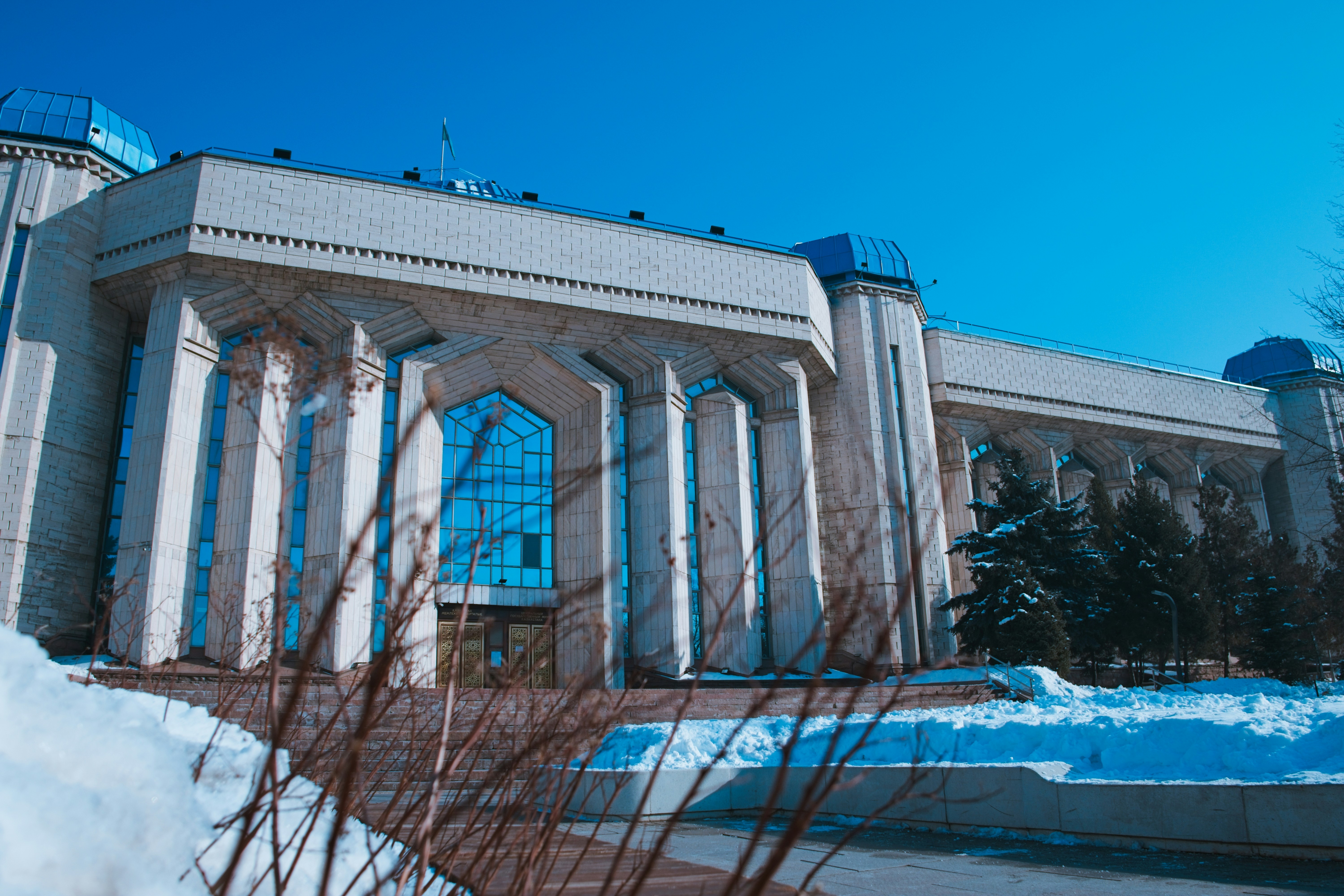 Majestic building with arched entrance framed by snow-covered landscape under a clear blue sky.