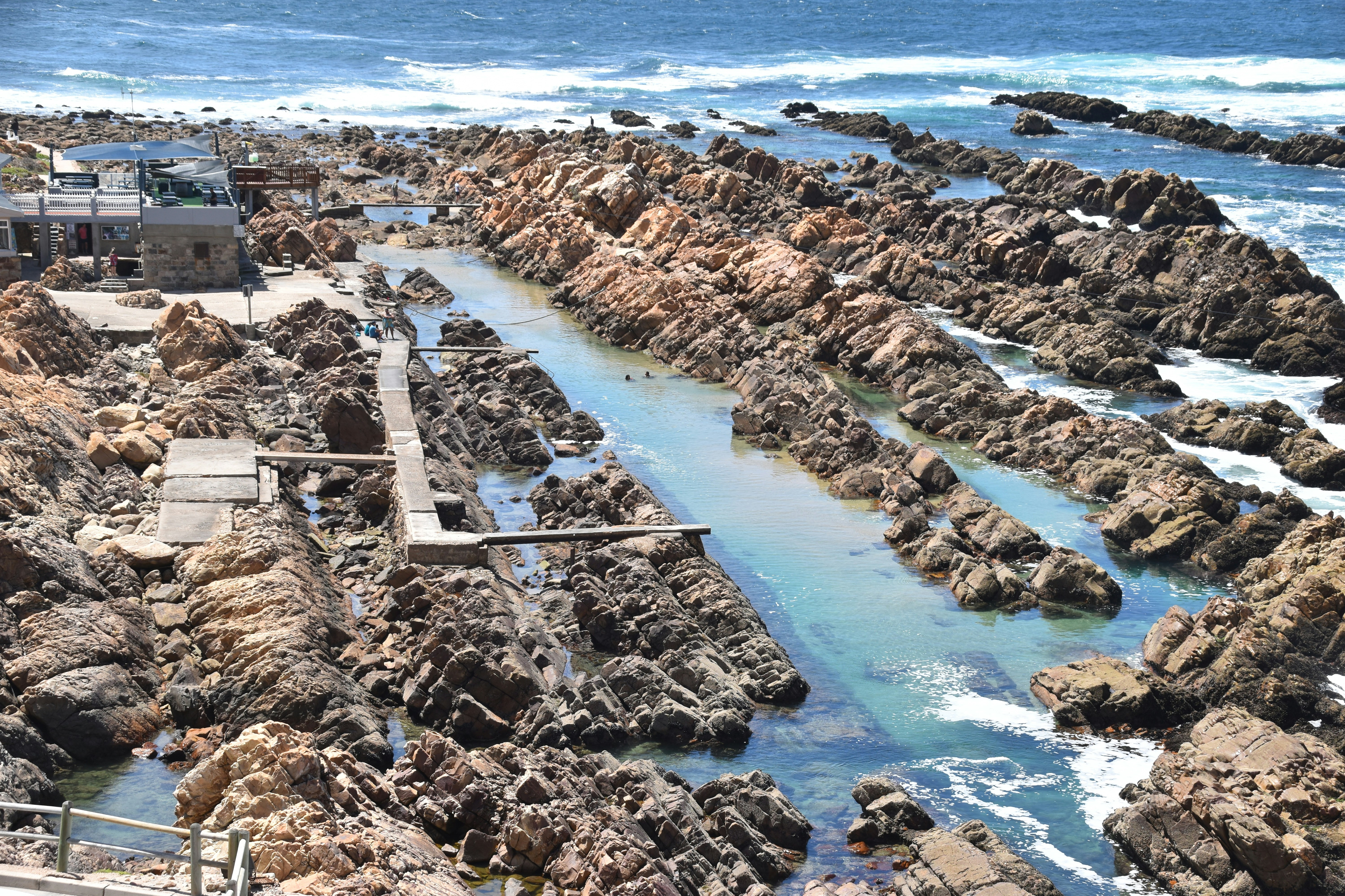 A large body of water surrounded by rocks photo – Free Mossel bay Image ...