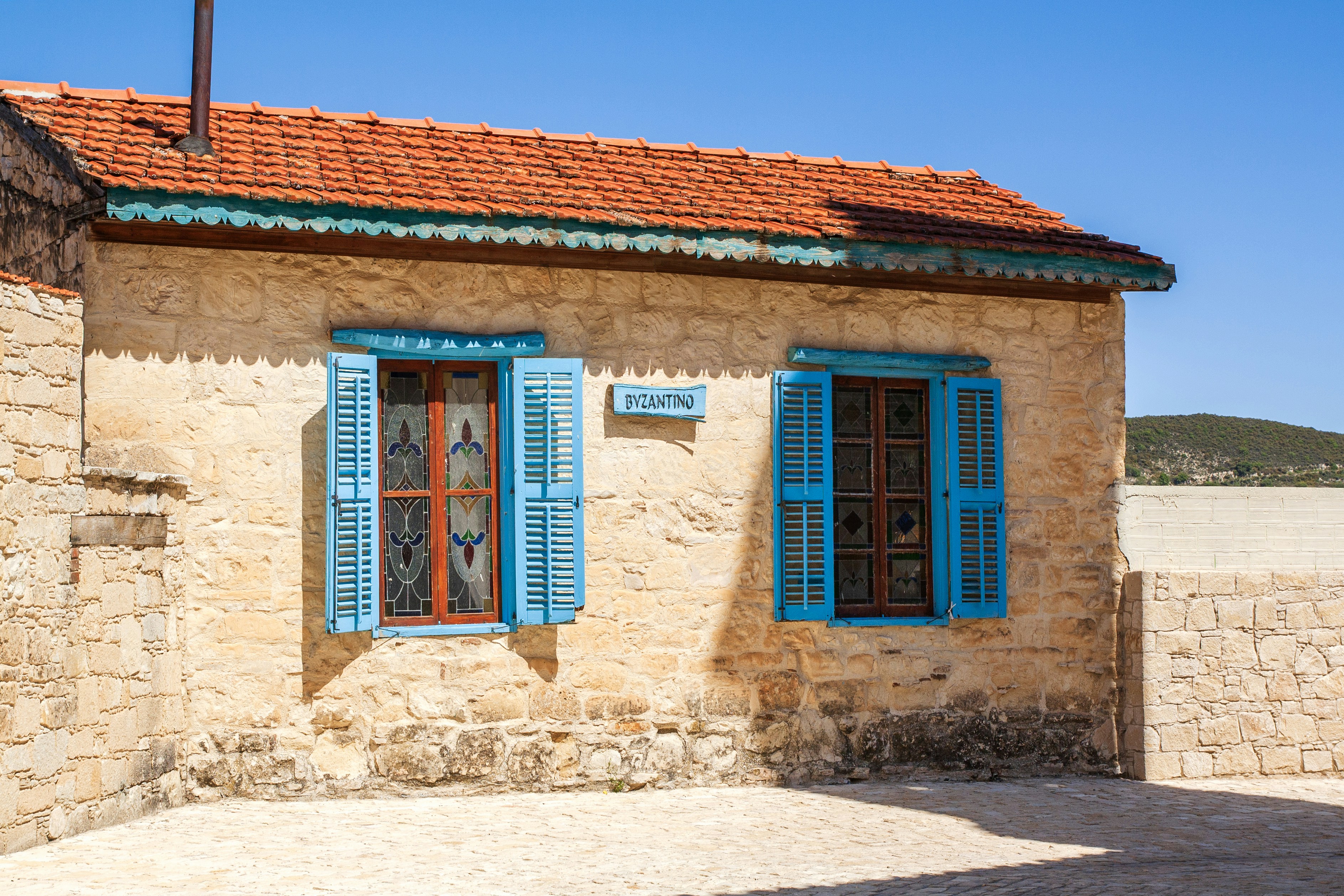 Stone house with vibrant blue shutters under a clear sky.