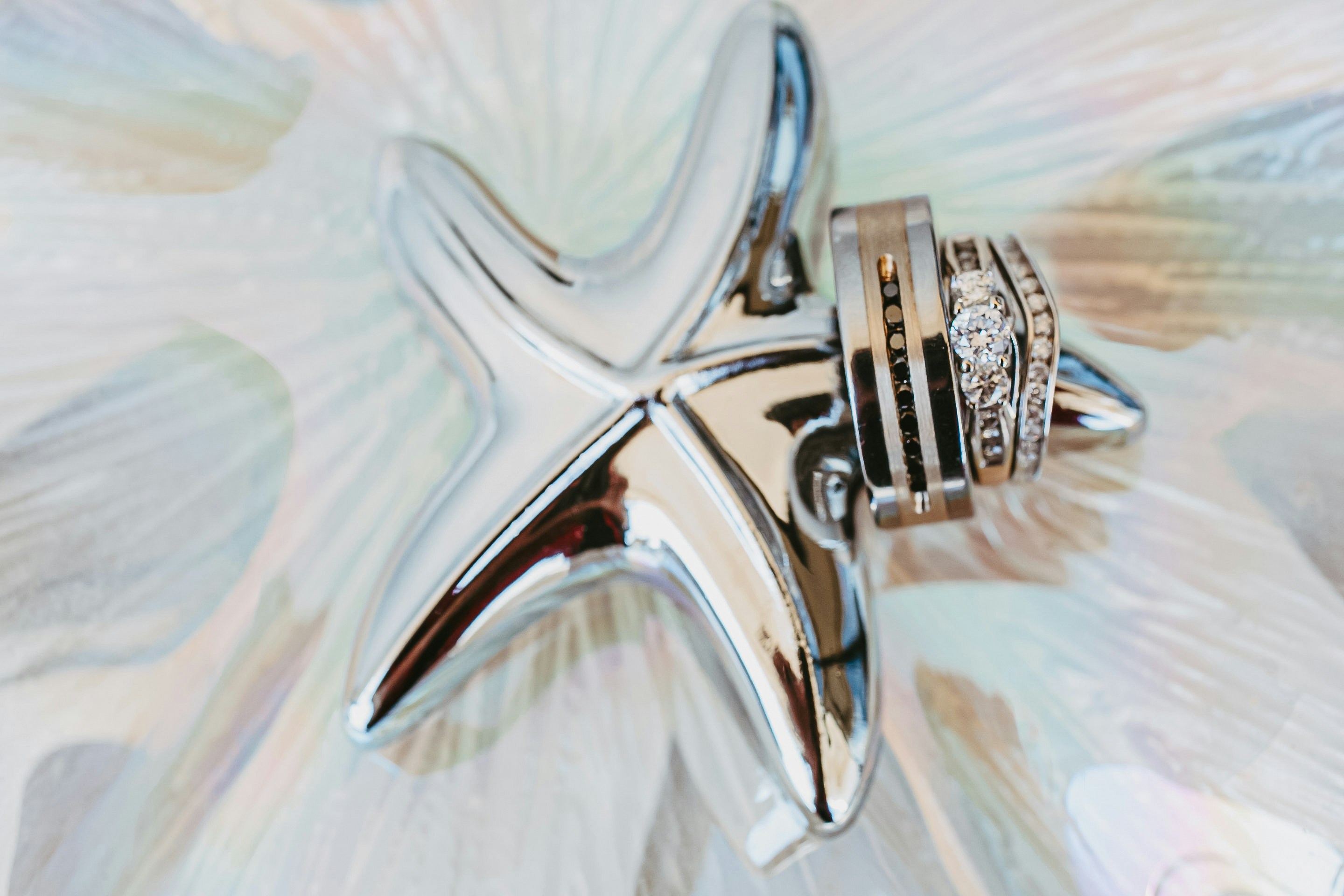 Polished X-ring: a gleaming clasp anchored on a soft, abstract backdrop