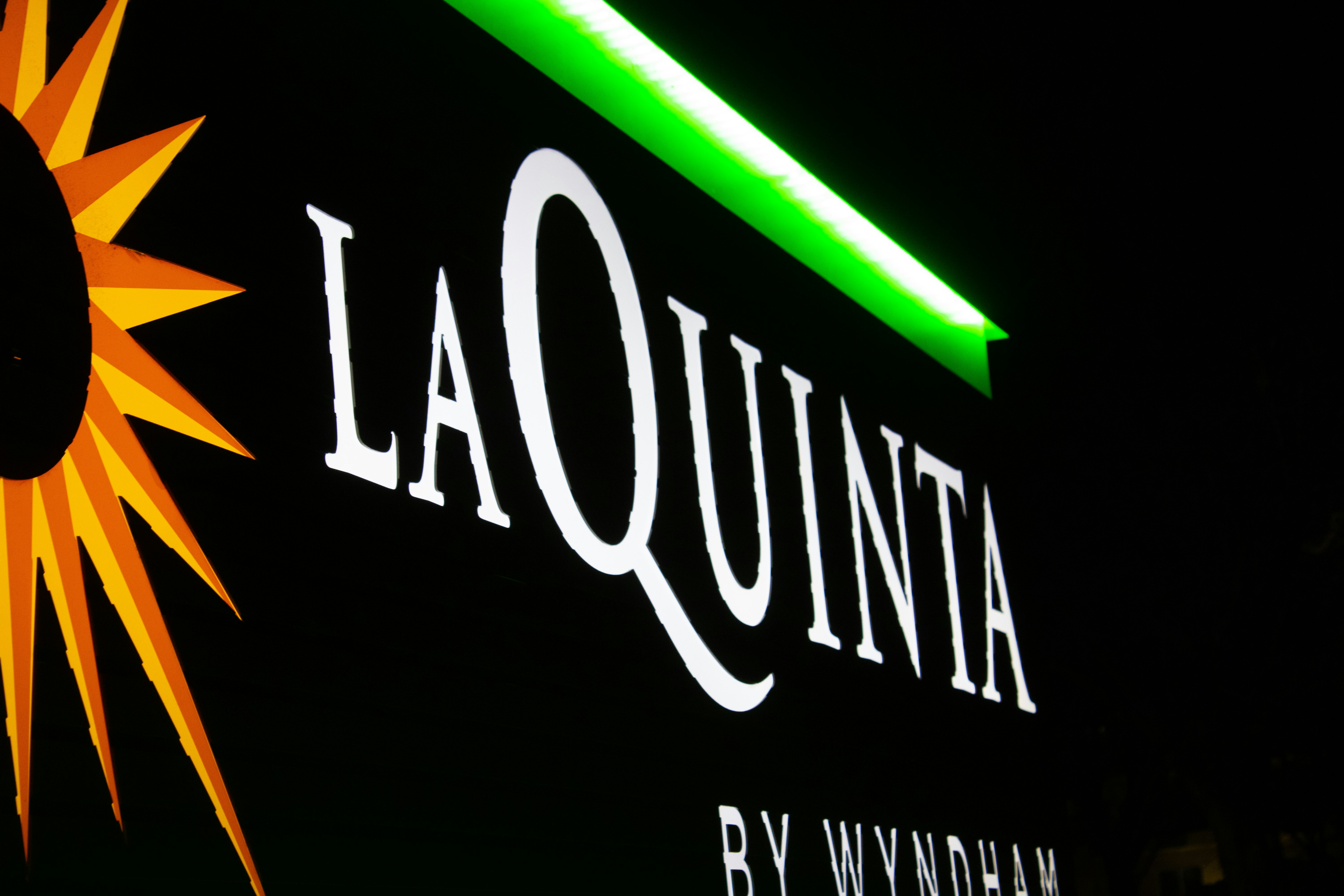 La Quinta at Night: Neon Sign with a Green Edge and Sunburst Logo