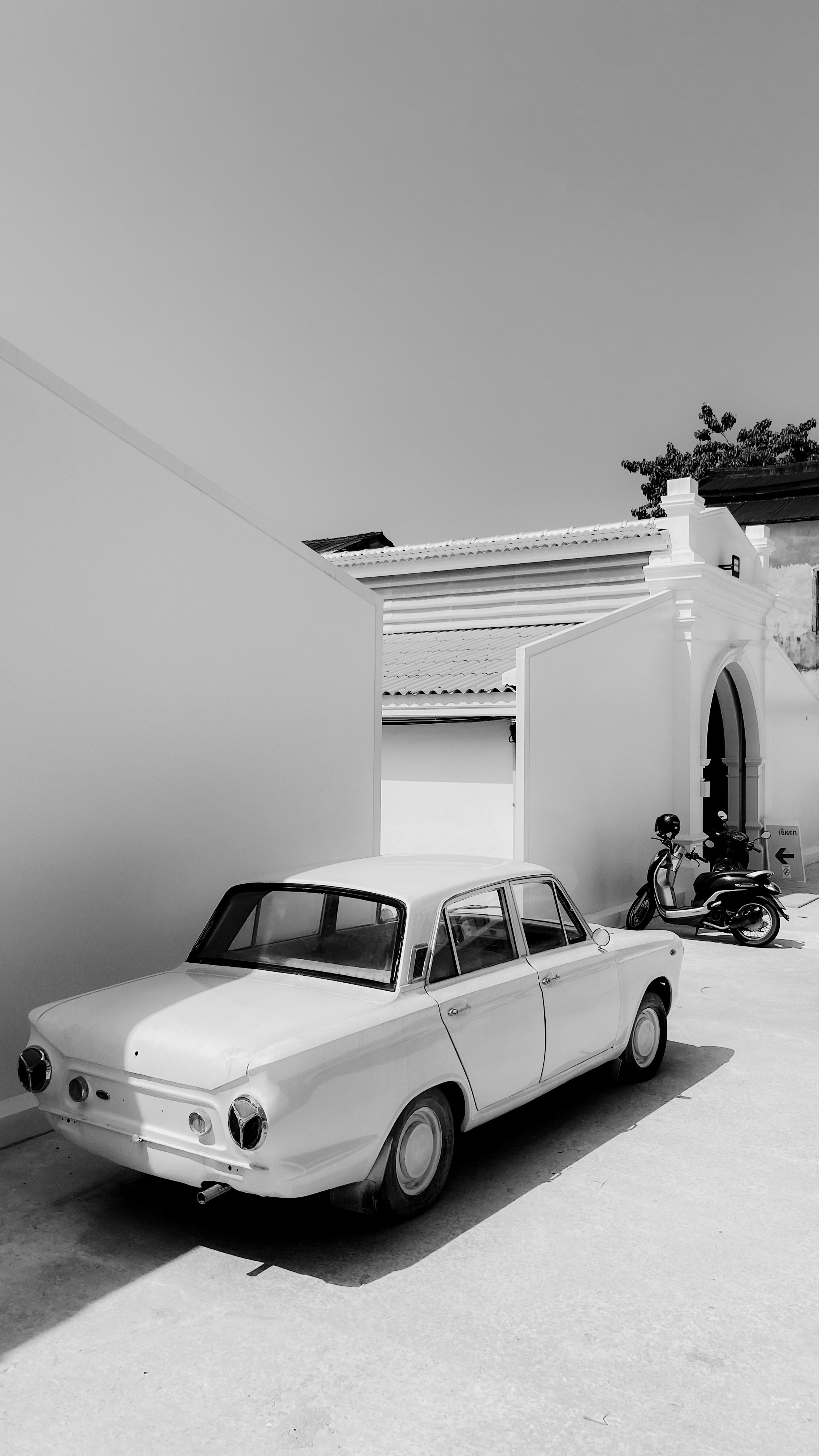 Monochrome Moment: A Classic Sedan Anchors a Sunlit Courtyard