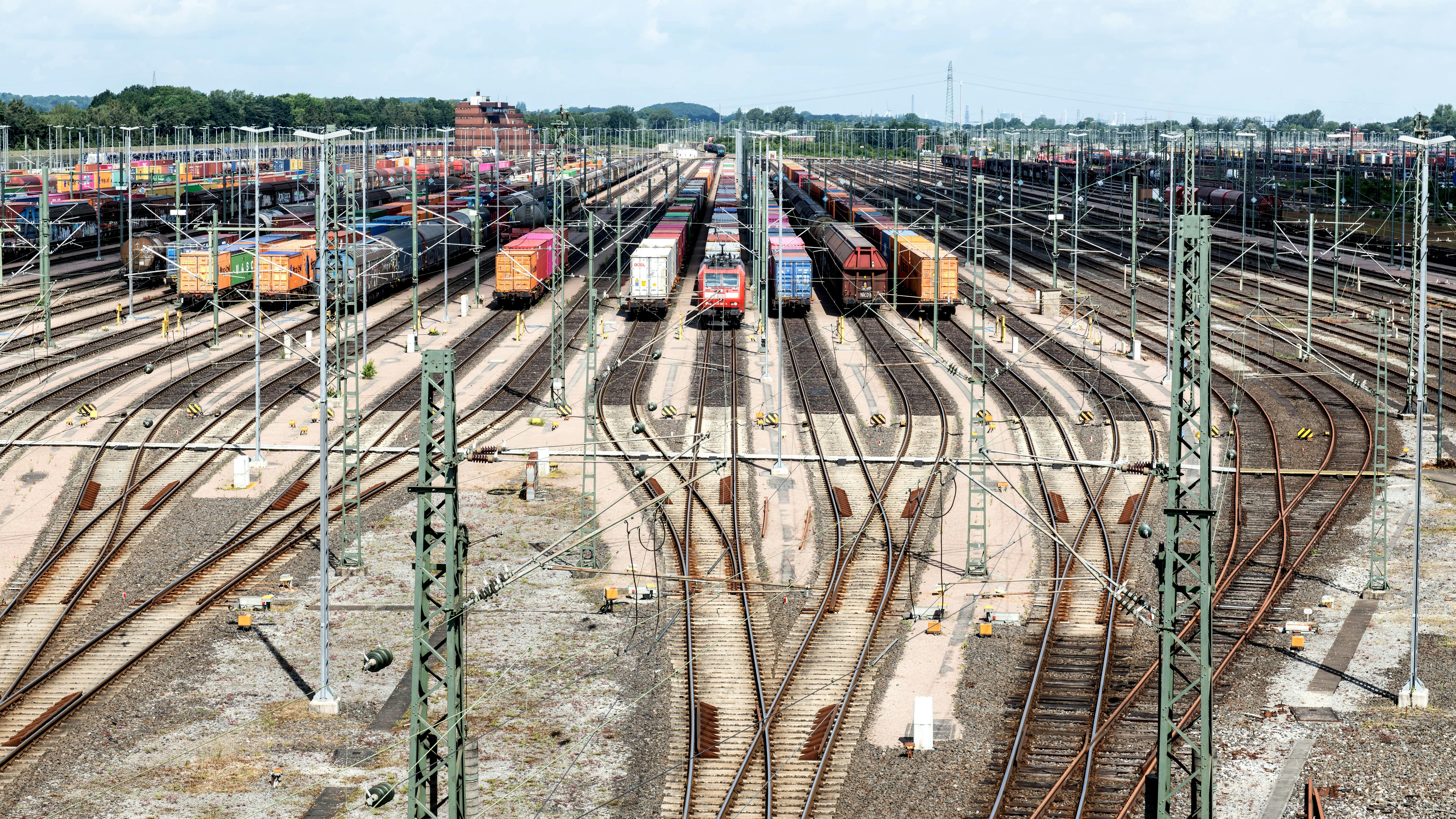 Rows of colorful trains aligned in a vast rail yard under a clear sky.