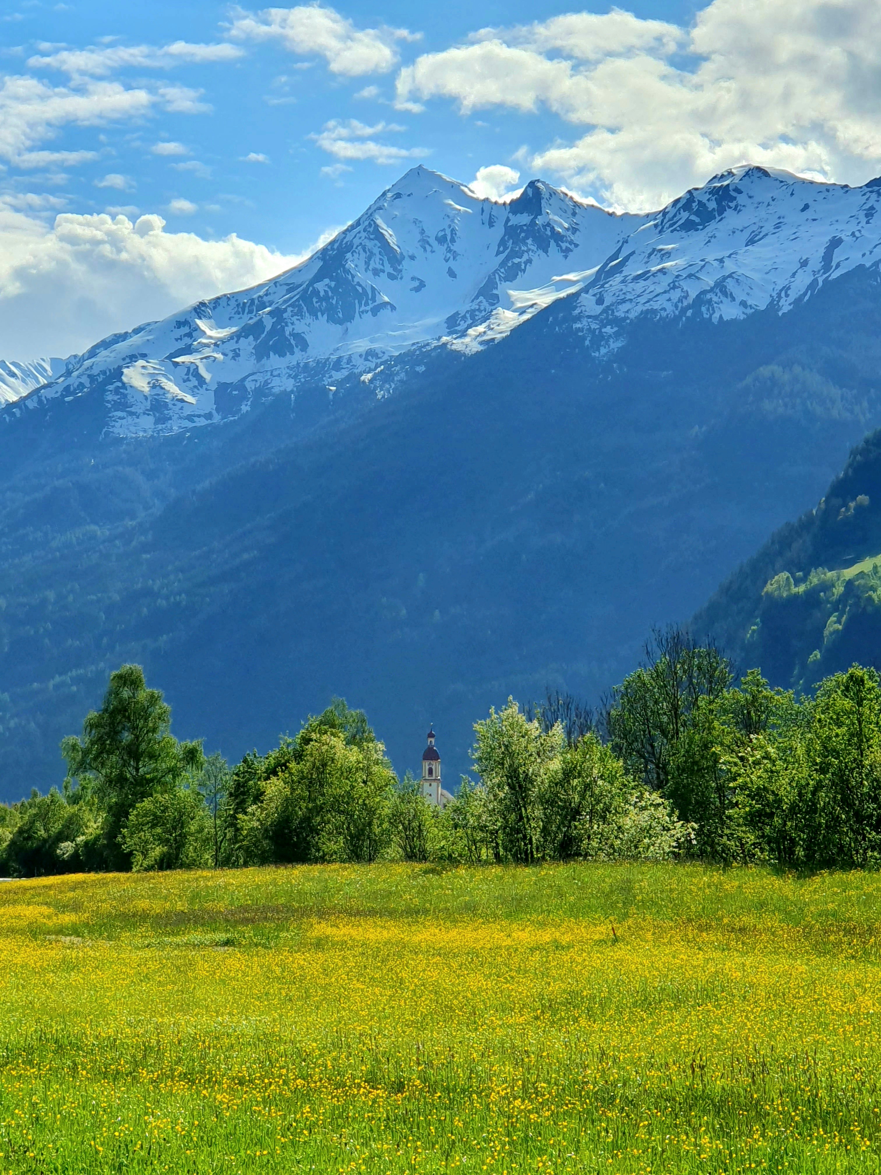 Spire in a Meadow: A Quiet Church at the Foot of Snowy Peaks