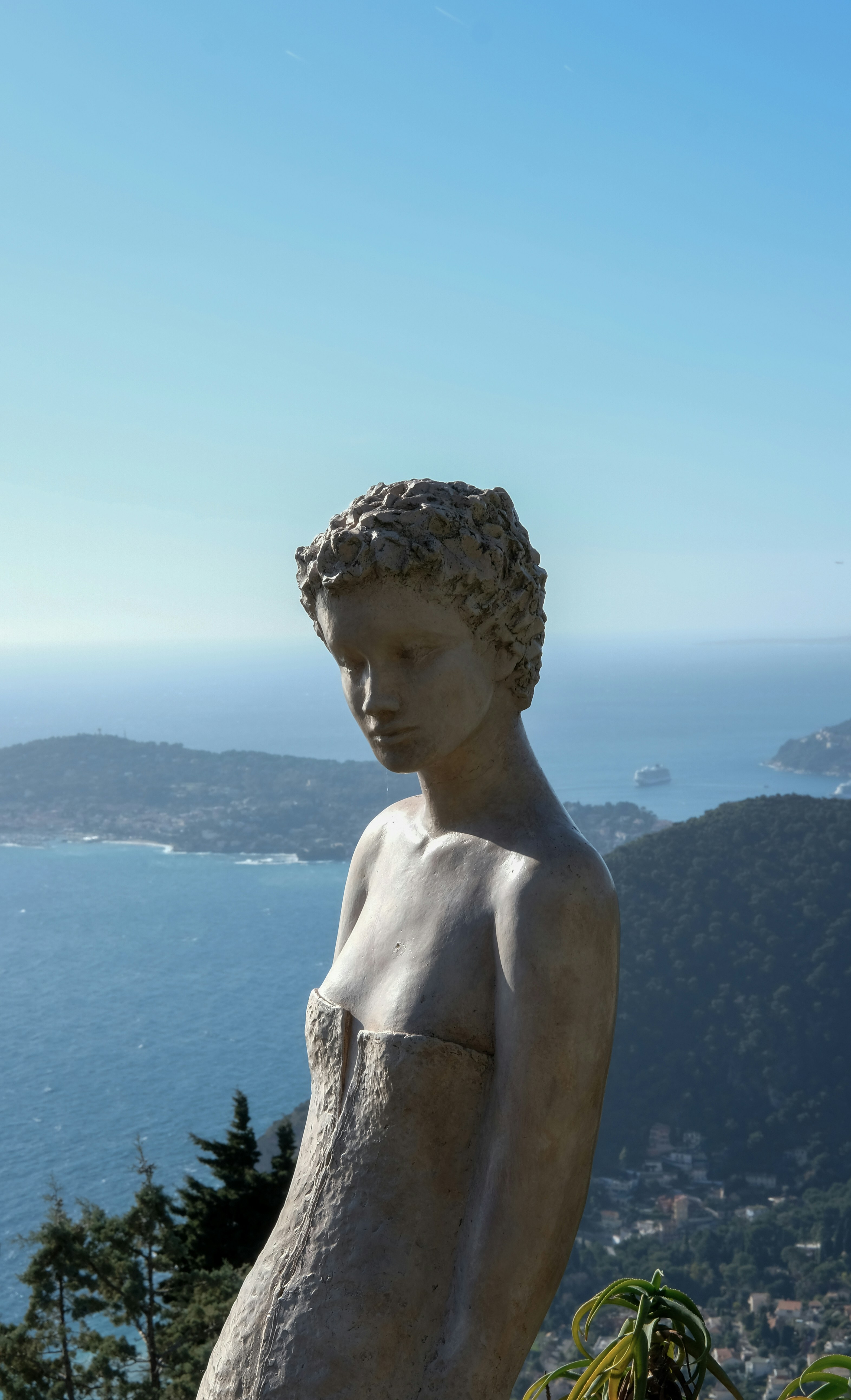 A statue of a woman standing in front of a body of water