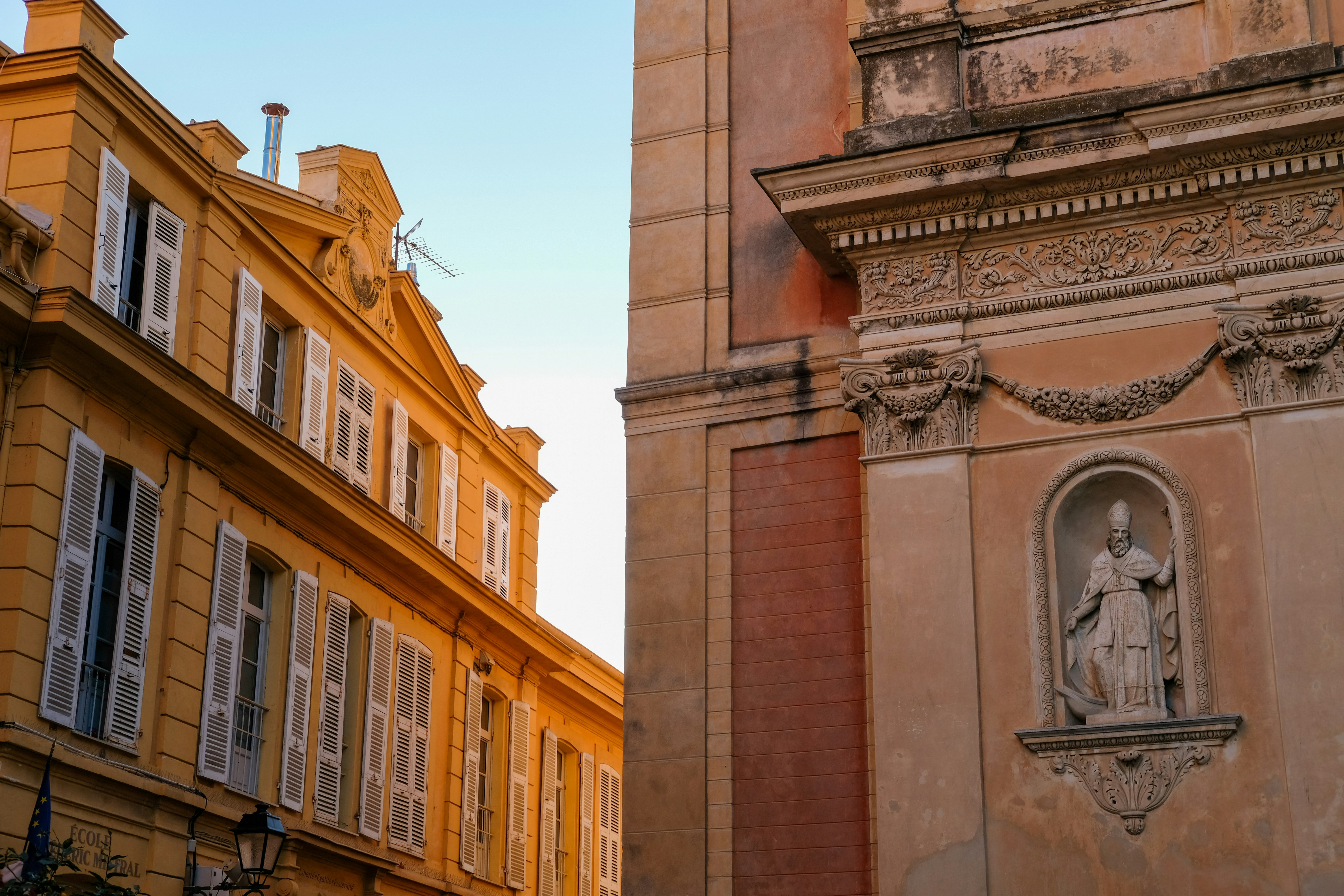 Warm sunlight casts a glow on historic buildings with detailed facades against a clear sky.