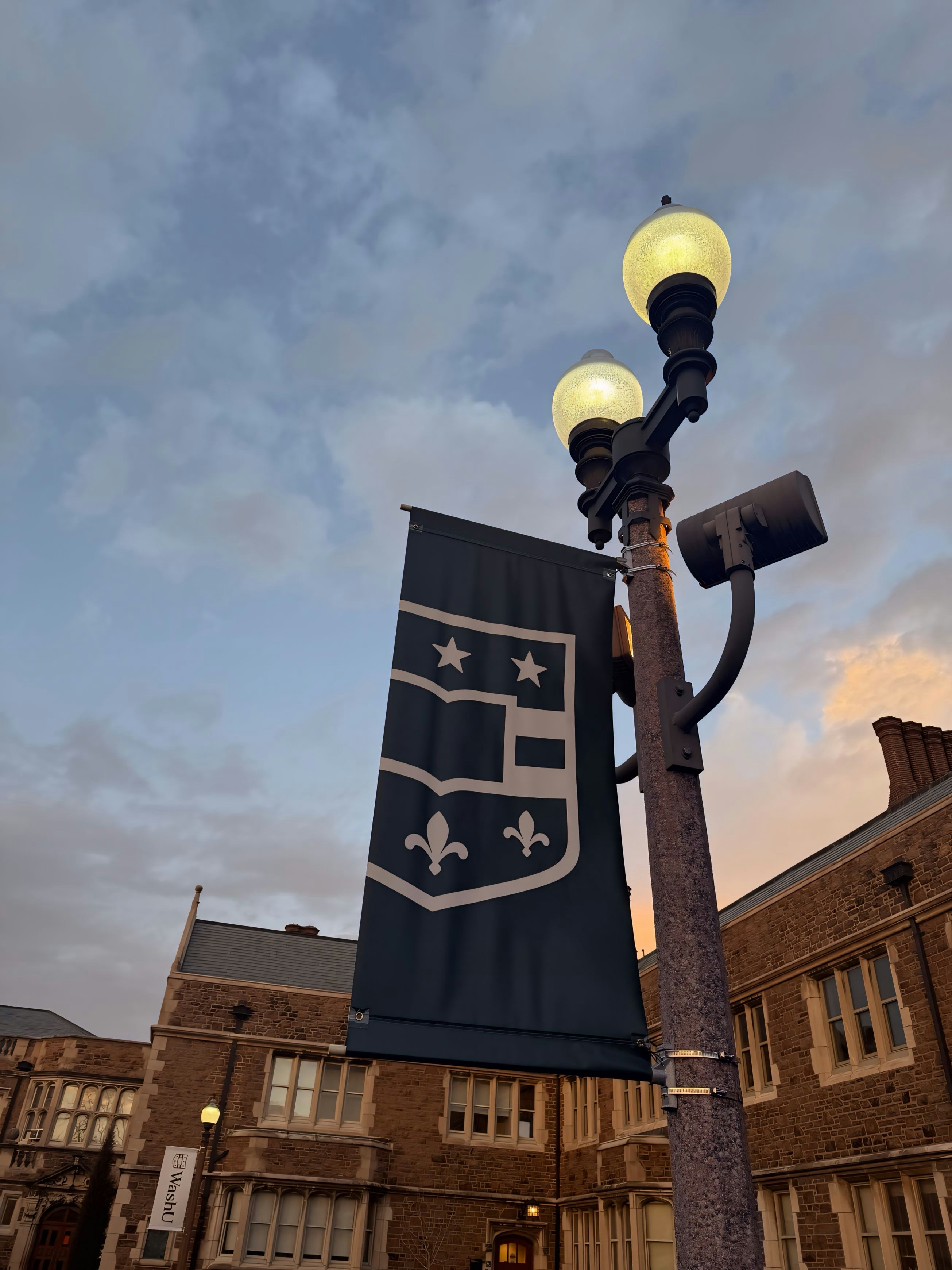 Crest on the Lantern: A Quiet Campus Banner at Dusk