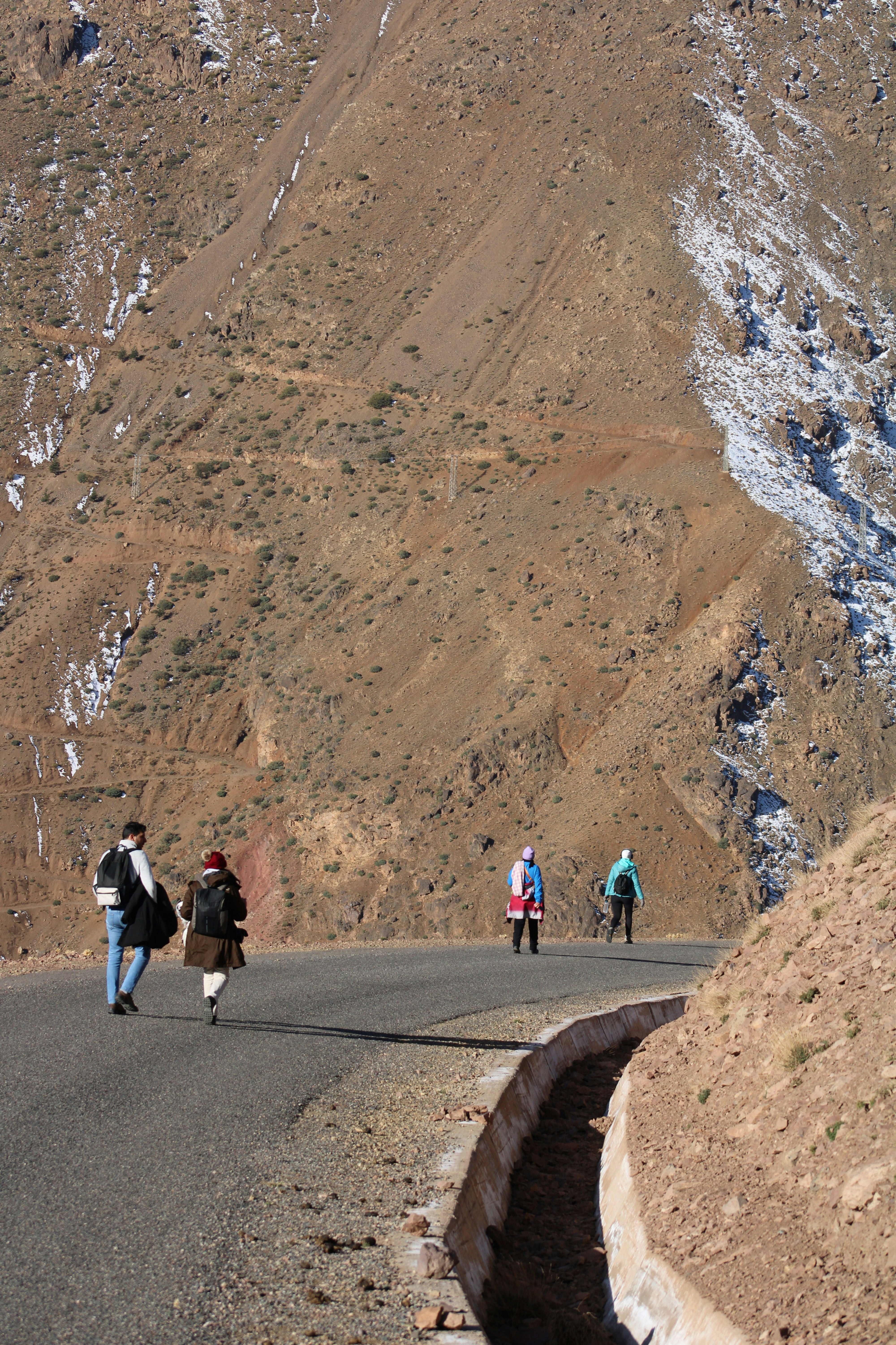 A group of people walking down a mountain road photo – Free Road Image ...