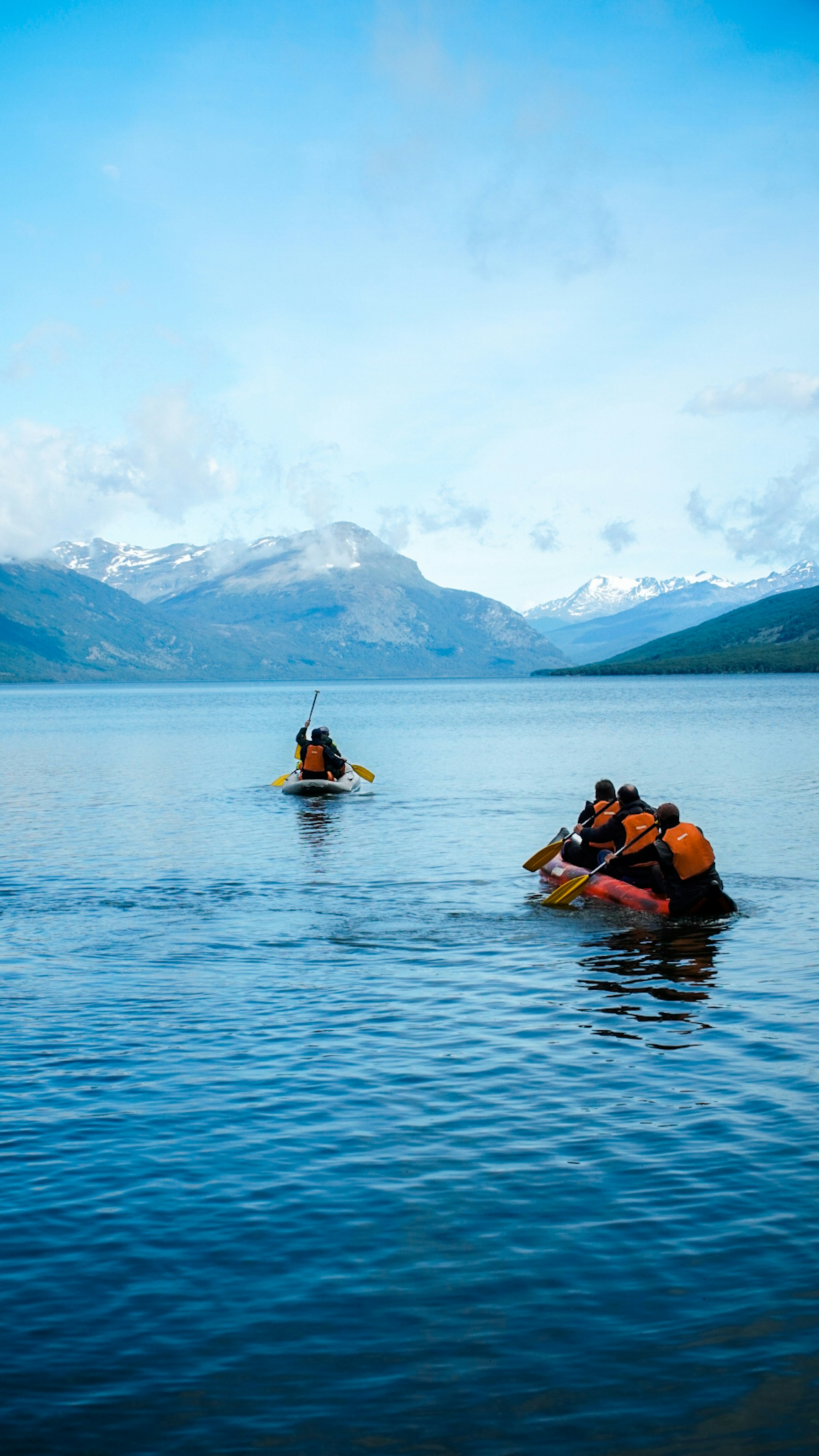 Orange-Vested Paddlers on a Glassy Glacier Lake Beneath Snow-Capped Peaks