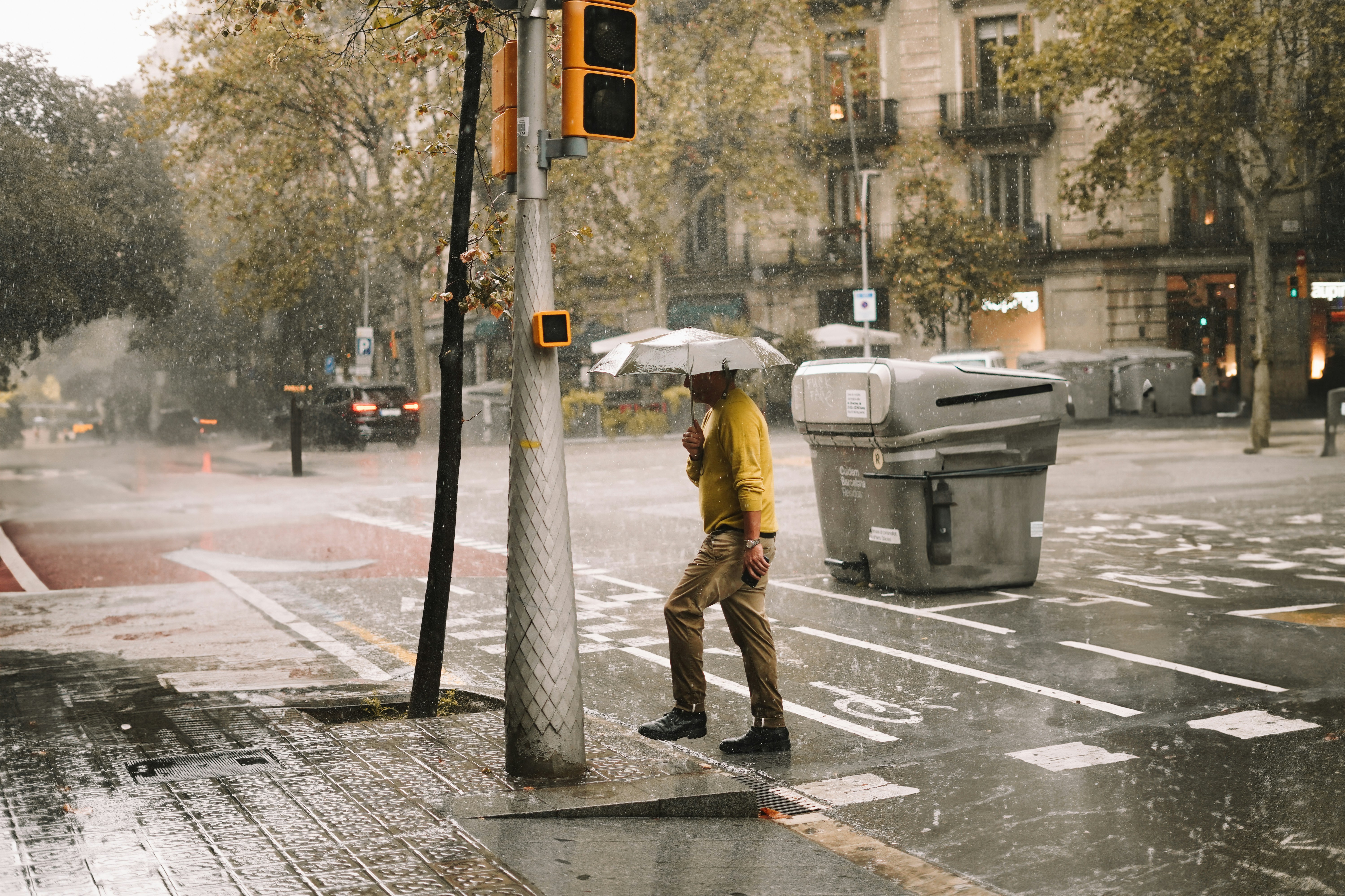 Man in yellow jumper escaping rain with his umbrella