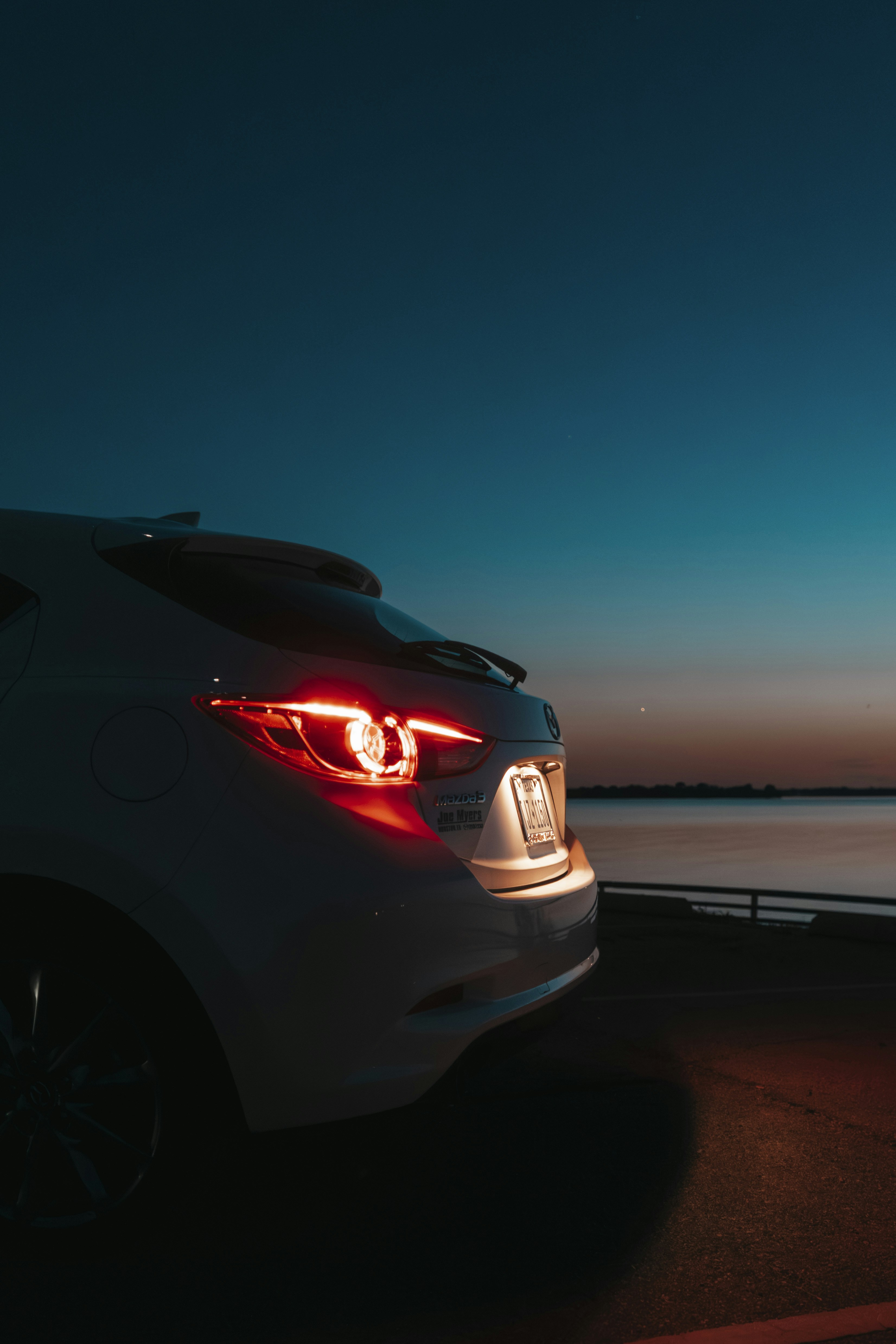 Tail Light at Dusk: A White SUV by the Waterfront