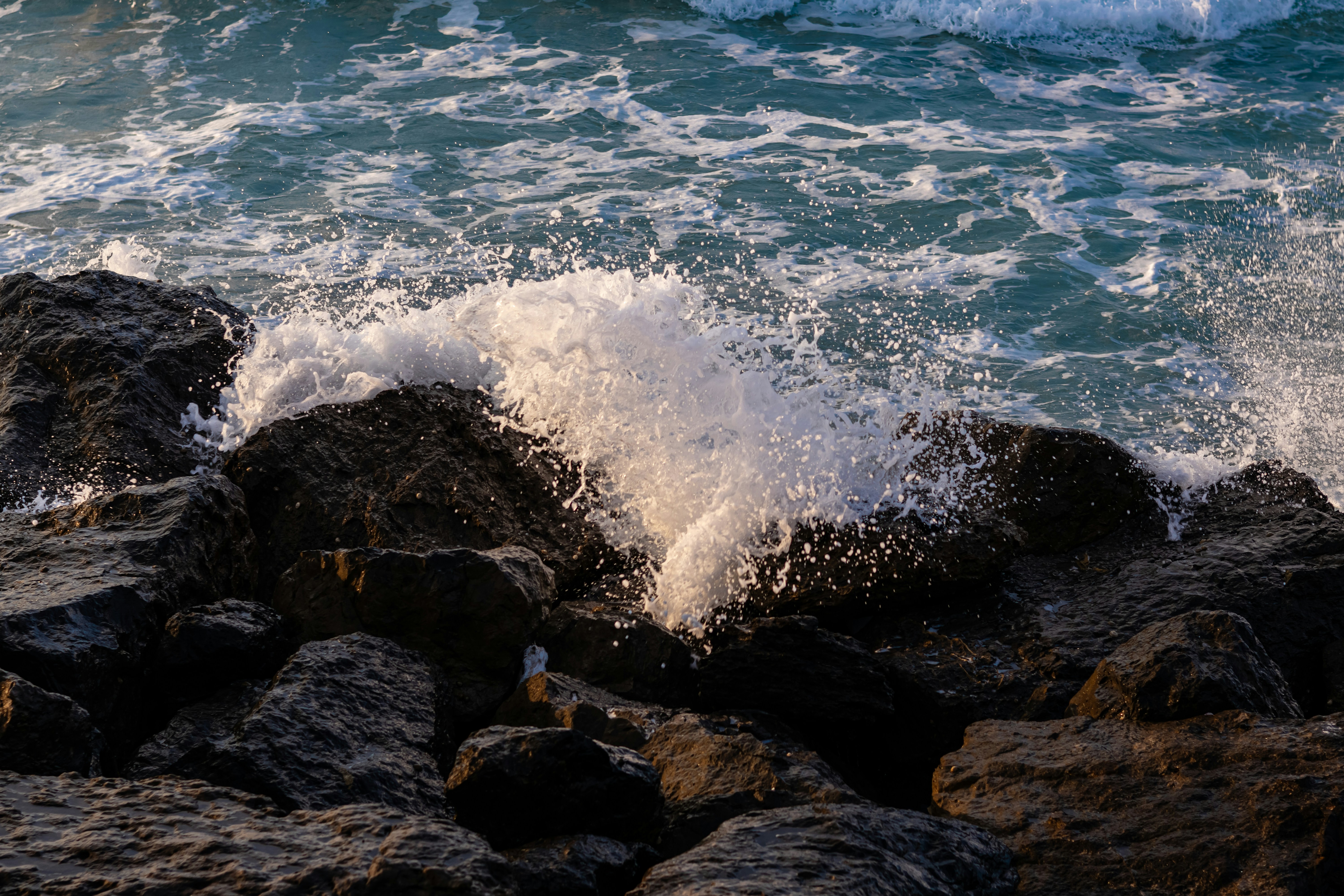 Una ola rompiendo en las rocas cerca del océano foto – Imagen de ...
