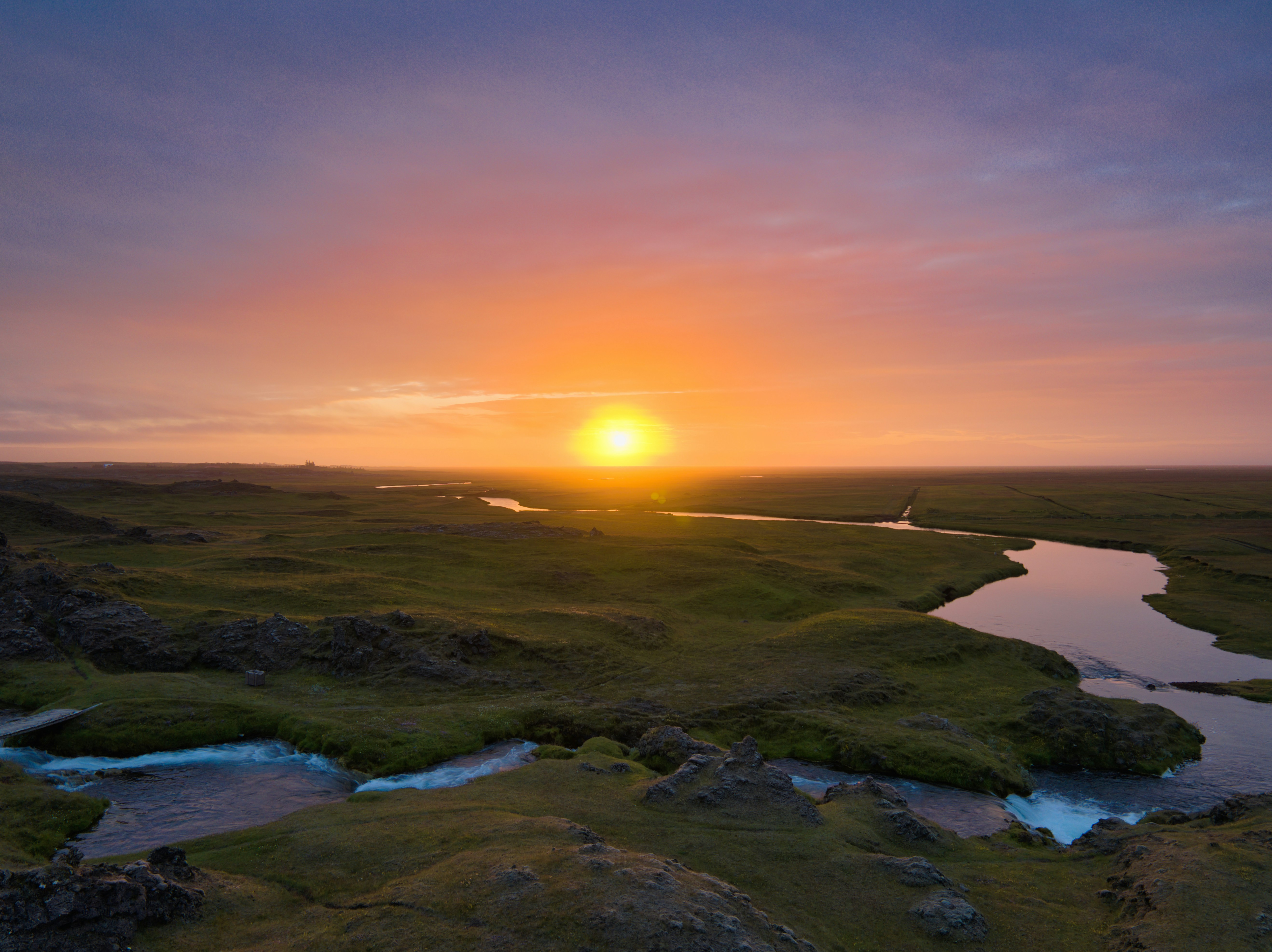 Sunset over mossy tidal flats with winding water channels