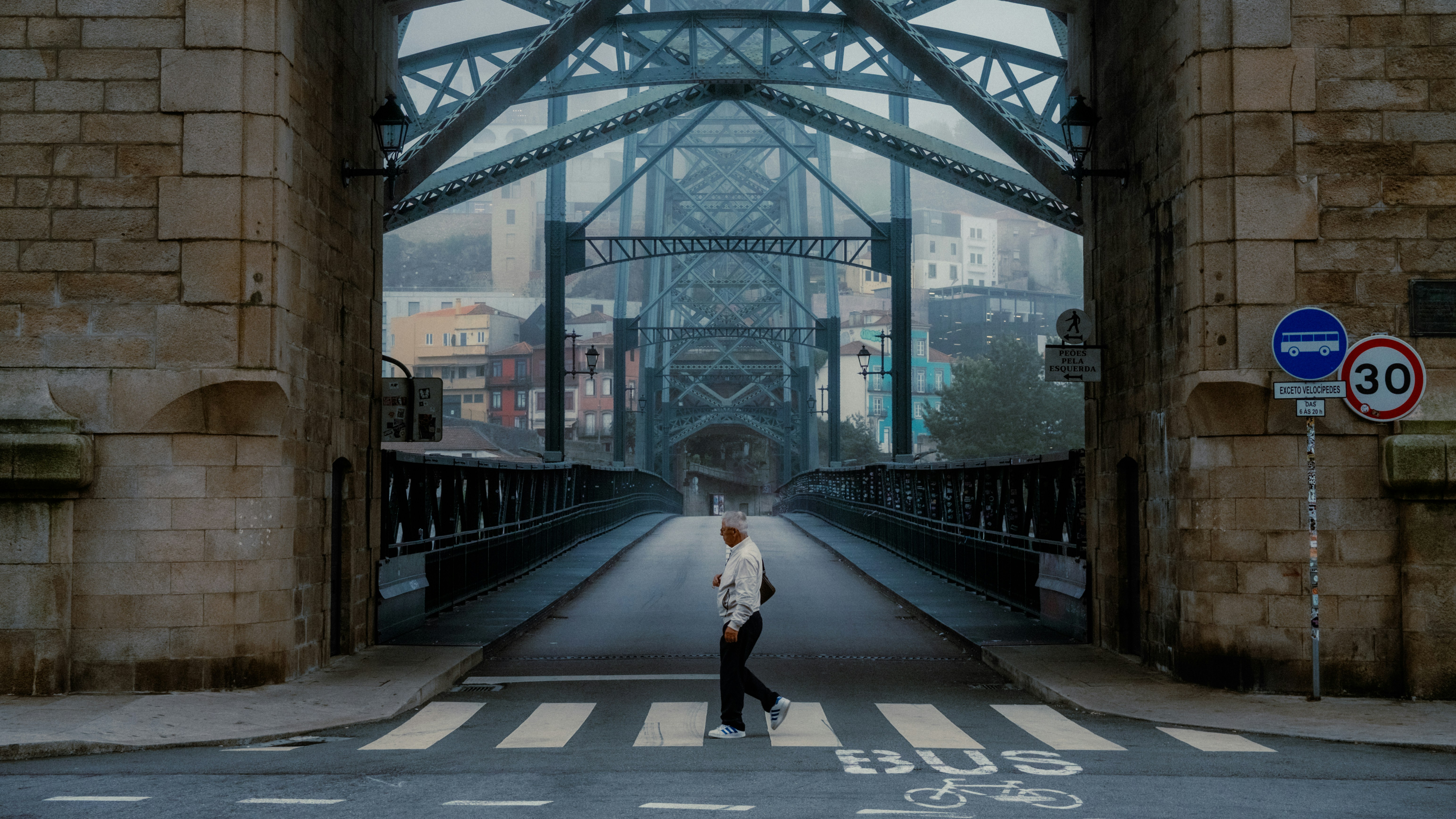 A person walking across a street under a bridge photo – Free Porto ...