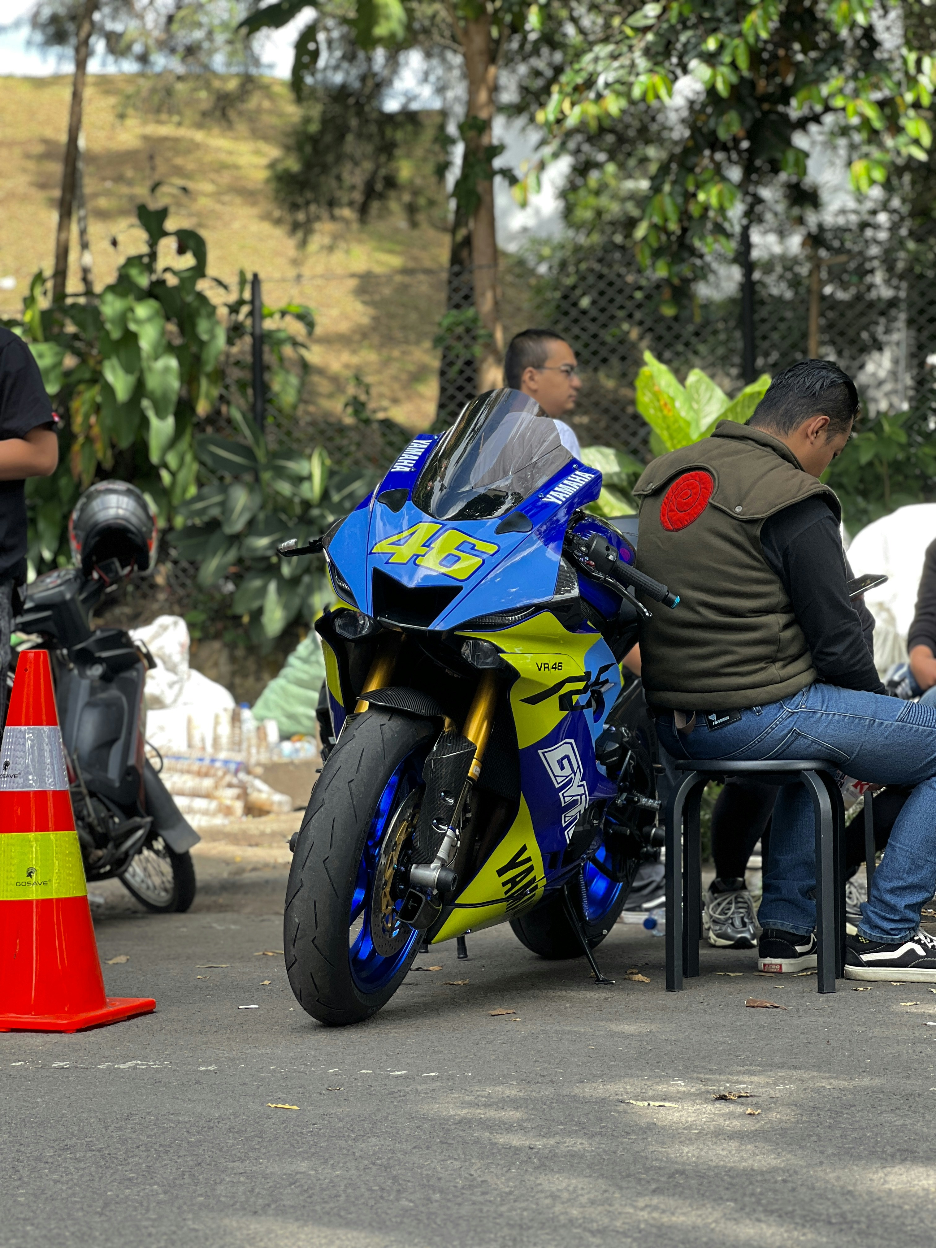 Blue Yamaha race bike with number 46 anchors a street-side pit scene