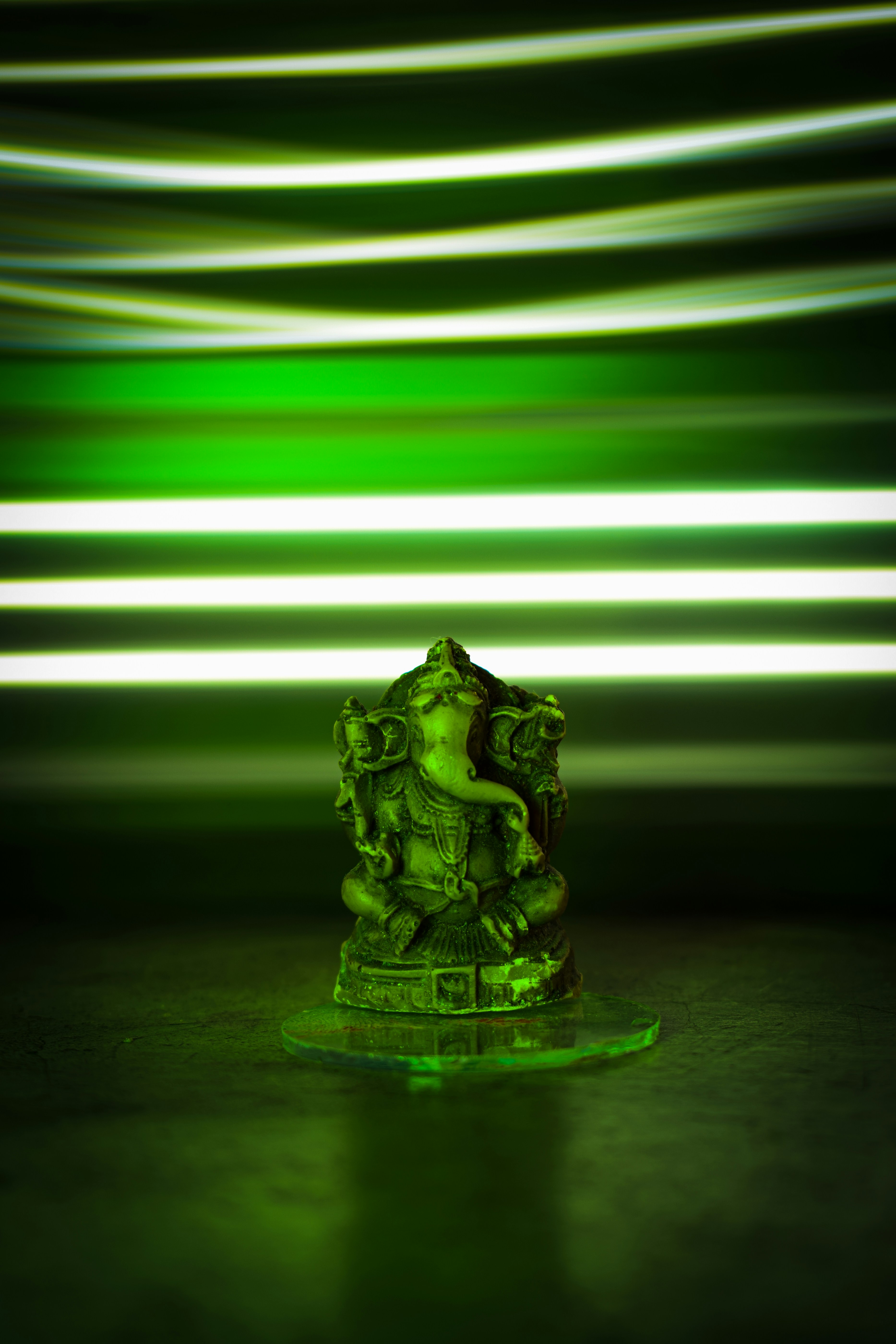 Intricately detailed Ganesha statue illuminated against dynamic green light trails, symbolizing energy and spirituality.