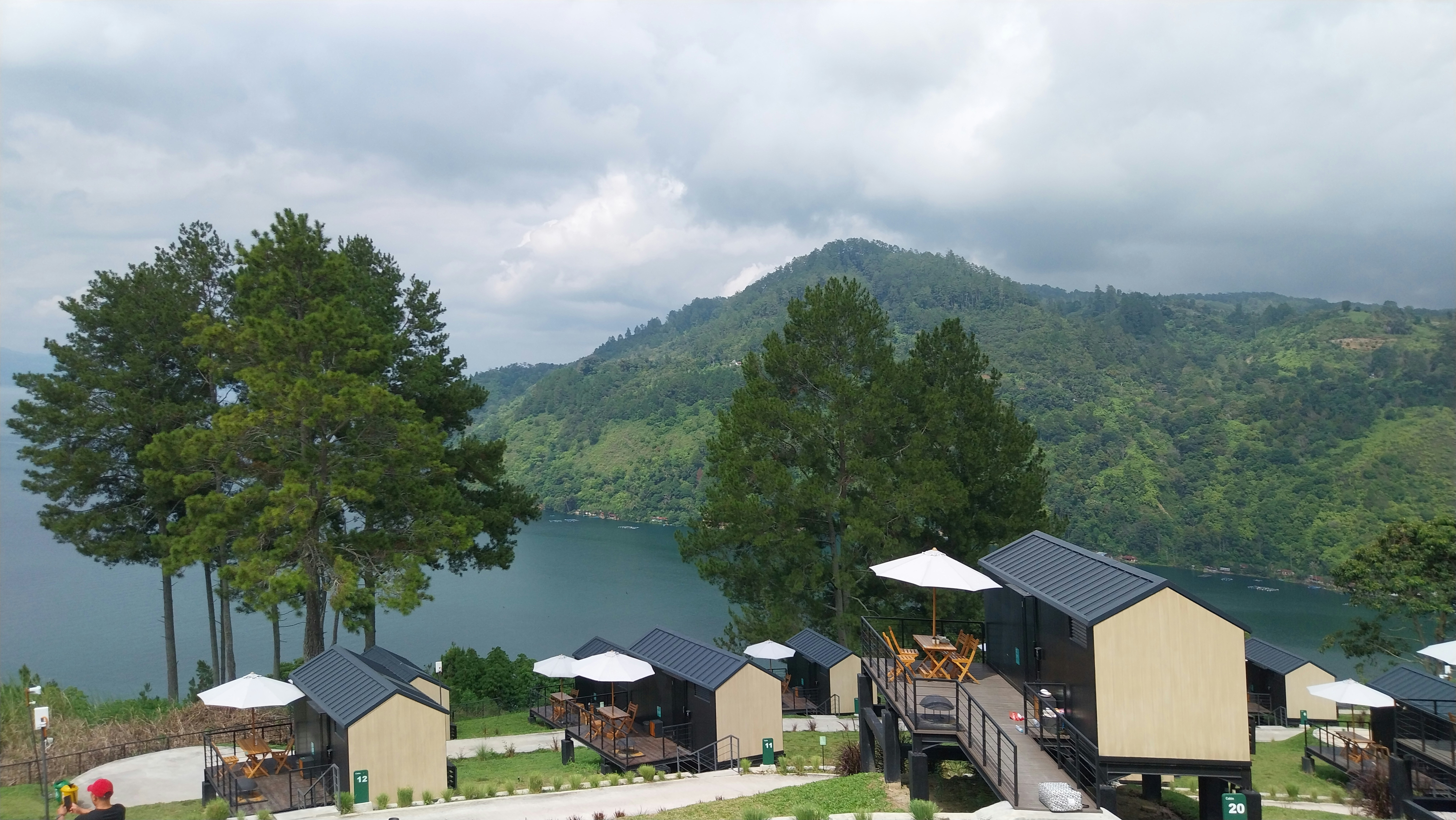 A group of cabins sitting on top of a lush green hillside photo – Free ...
