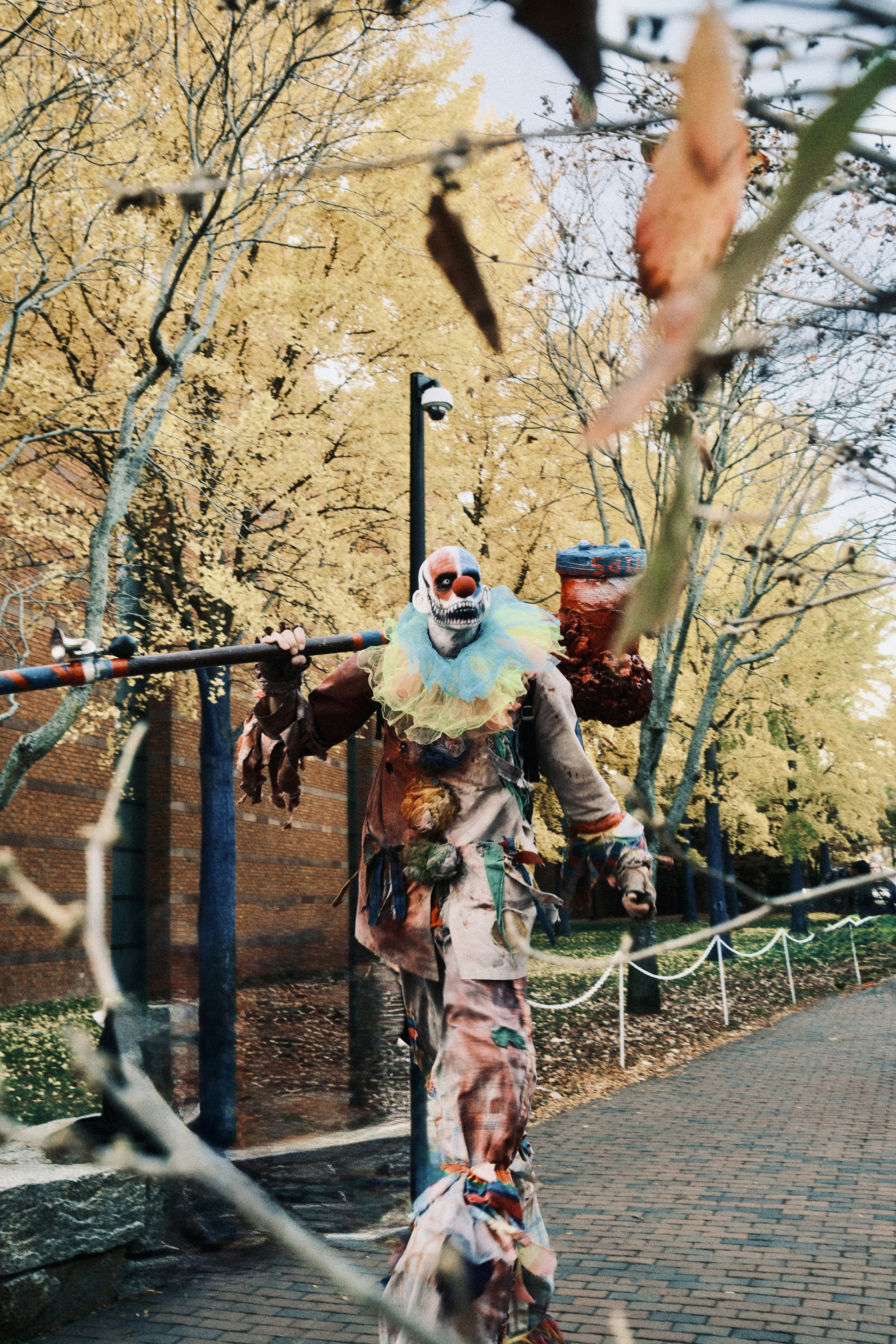 A clown walking down a sidewalk next to a fence photo – Free Halloween ...