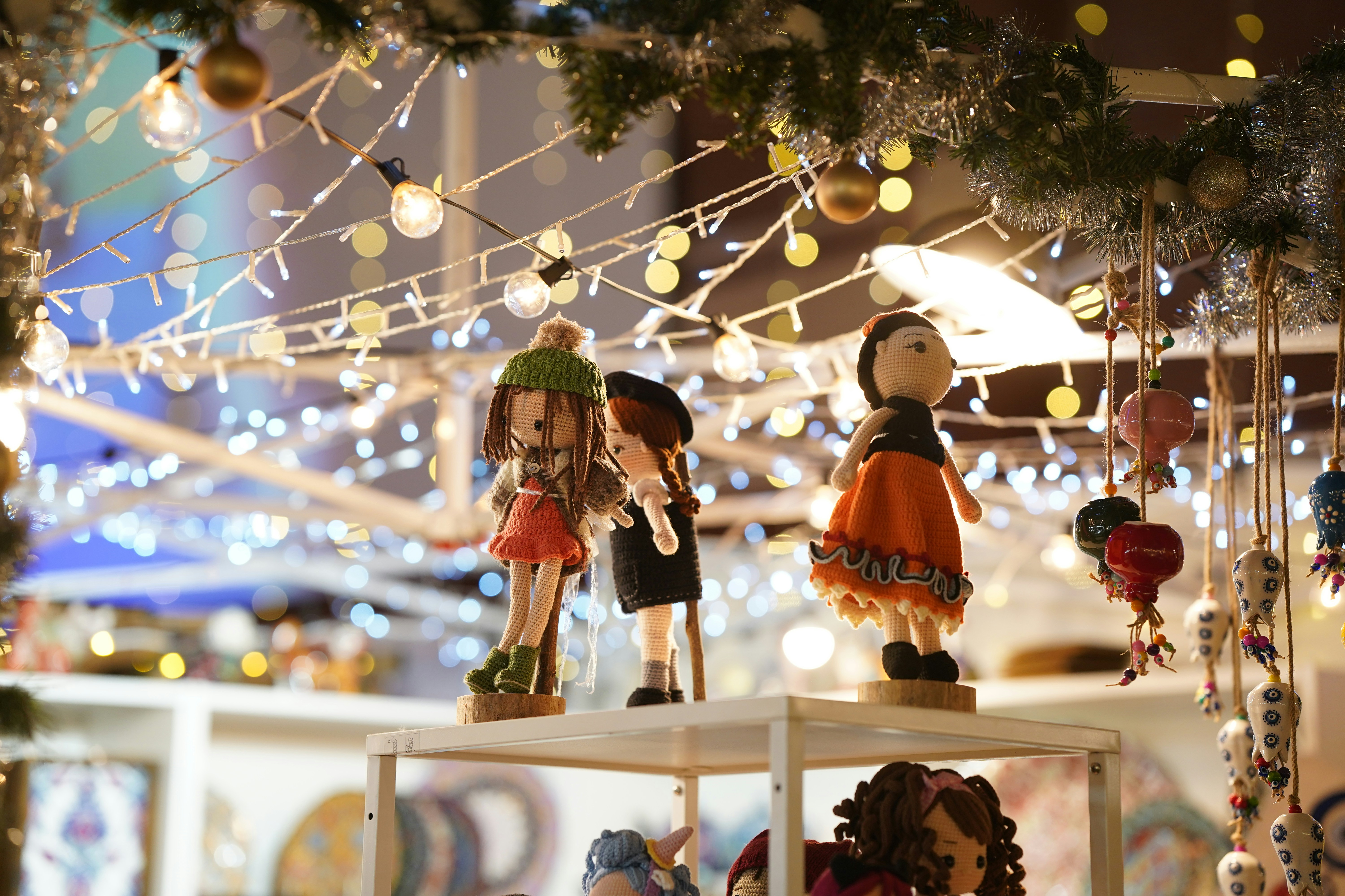 Festive Plush Figures on a Display Shelf Beneath Holiday Lights