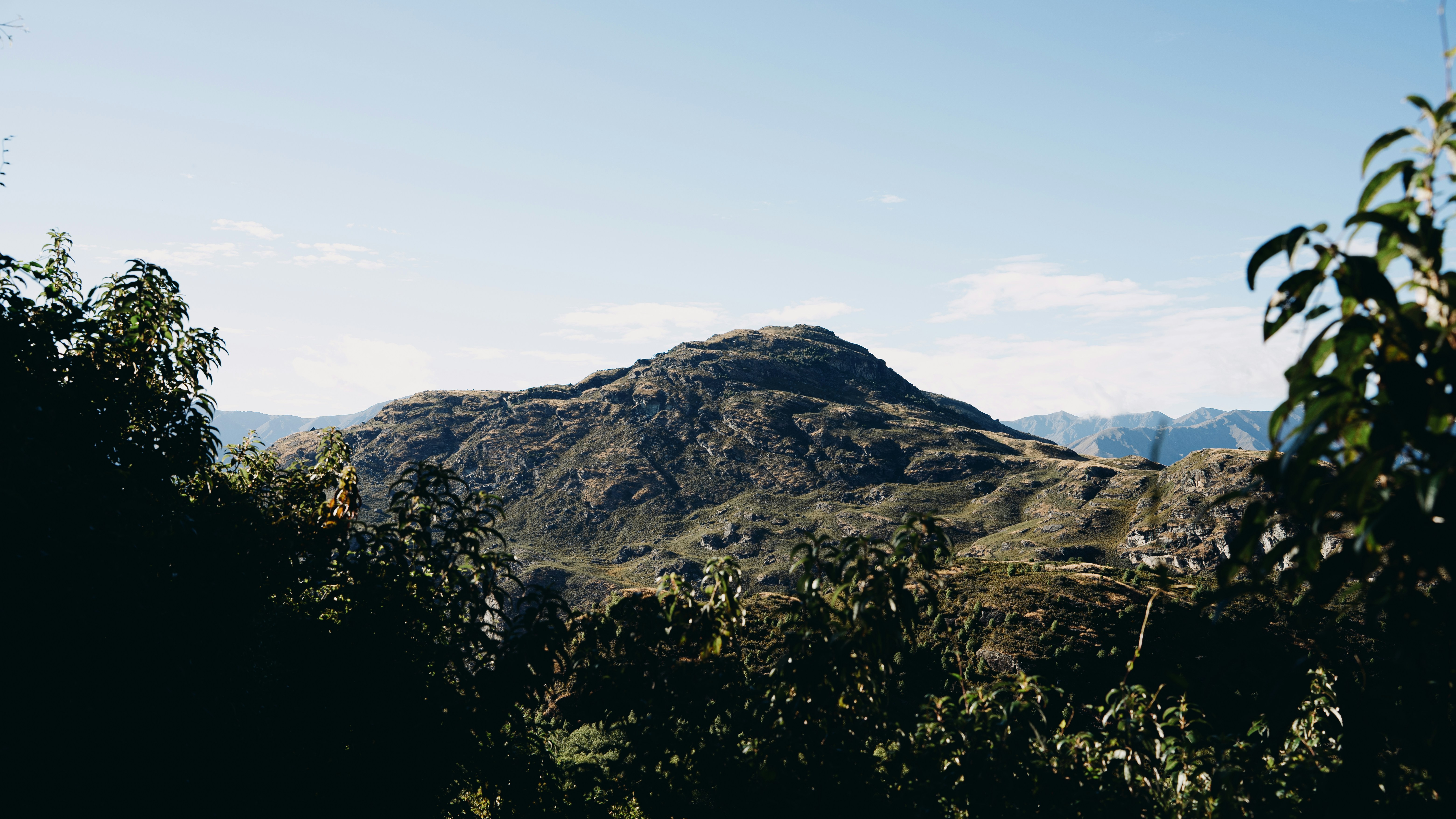 Distant Crest: A Mountain Ridge Framed by Quiet Foliage