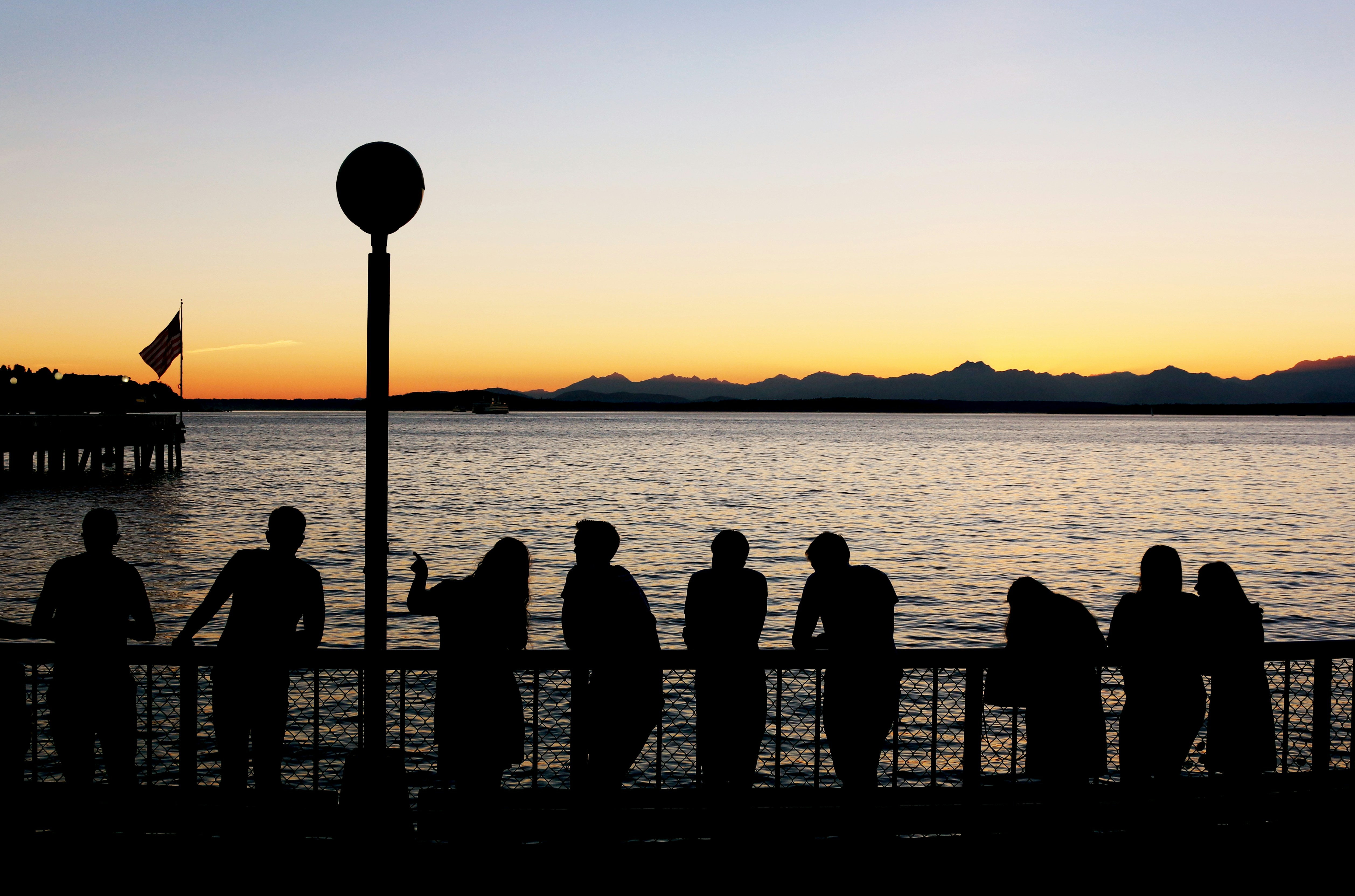Dusk by the Pier: Silhouetted Figures Against a Golden Horizon