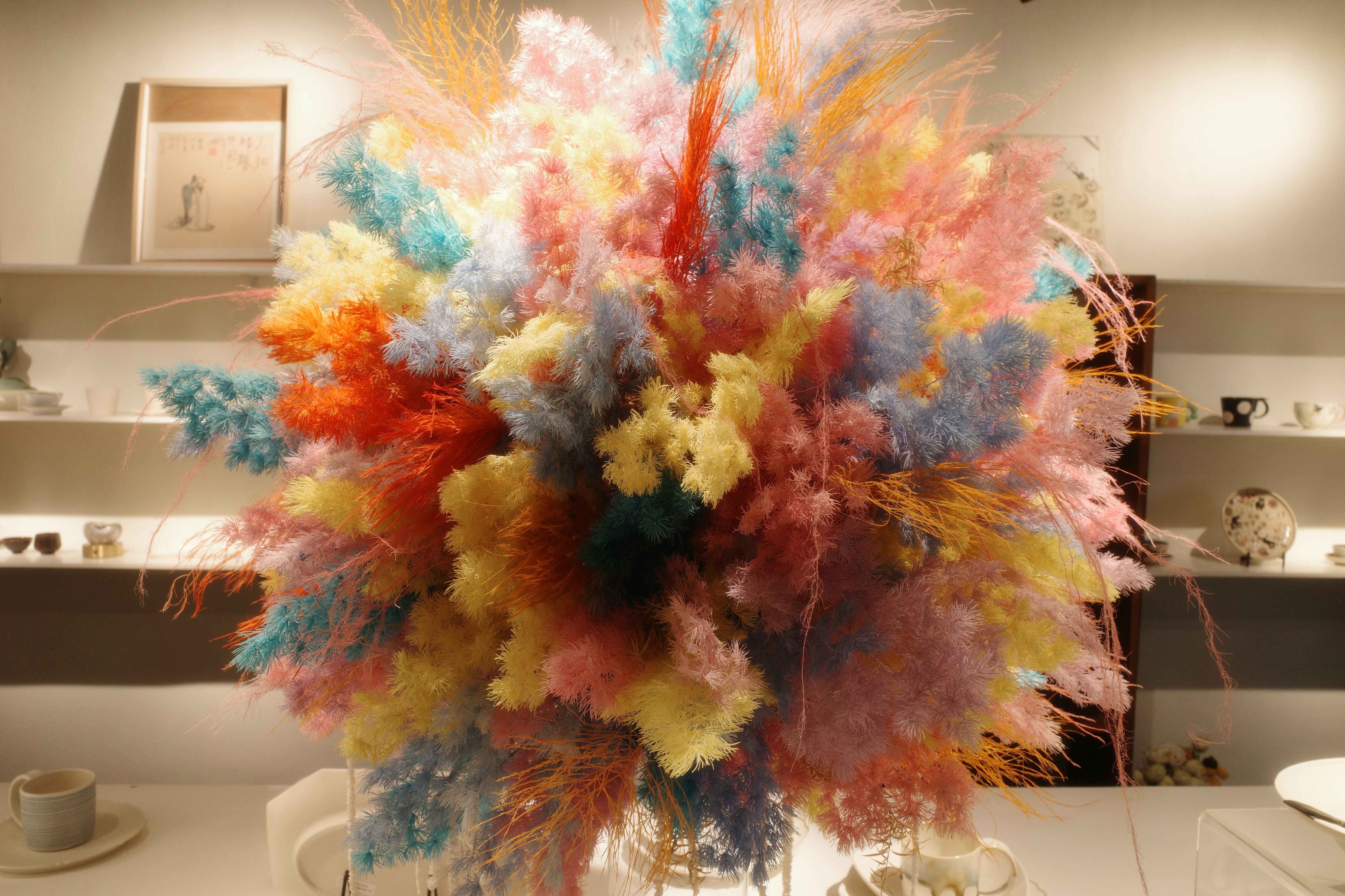 Colorful display of feathery textures in a vibrant fusion of pink, blue, yellow, and orange against a minimalist backdrop.