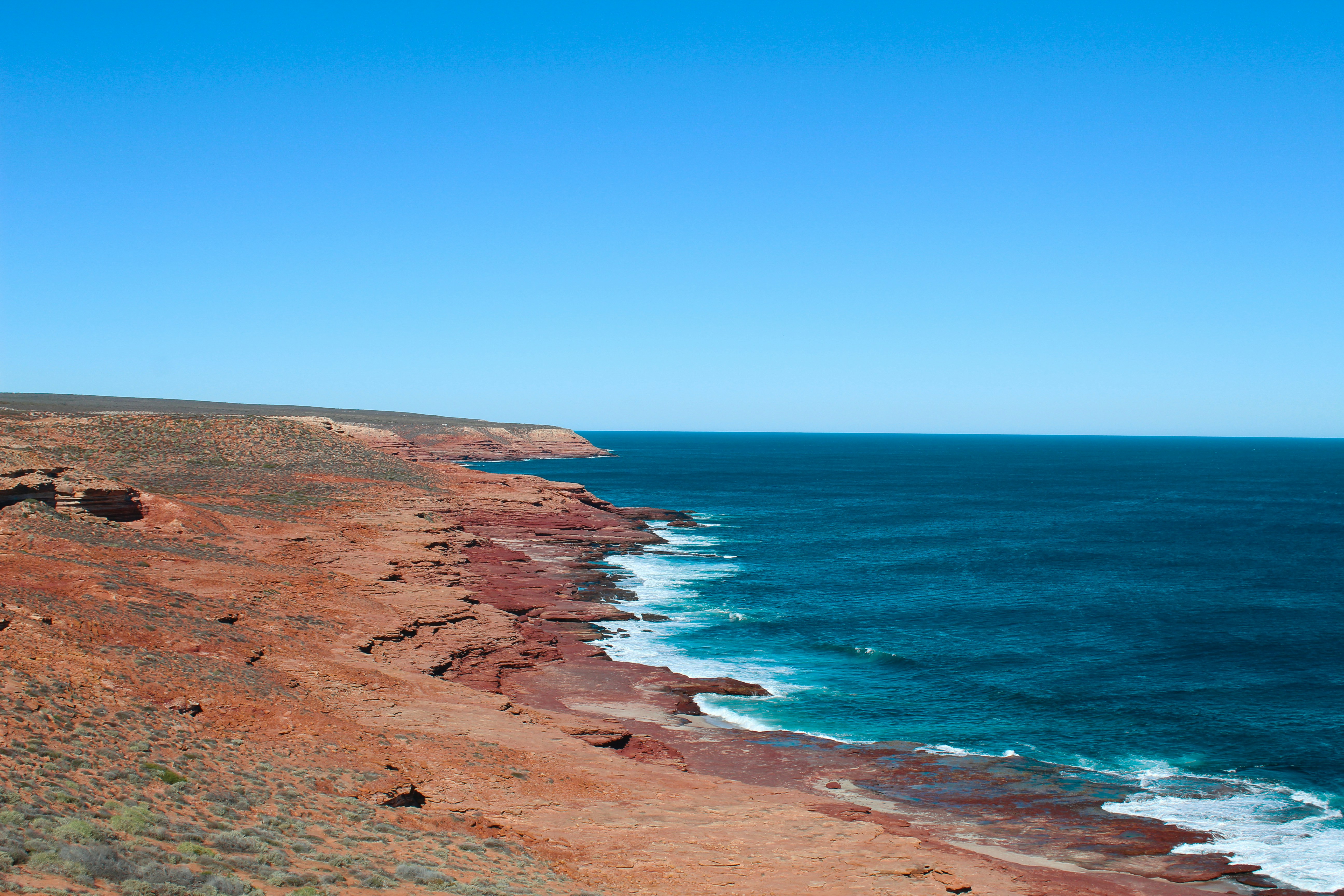 Crimson Coastline's Embrace with the Azure Sea