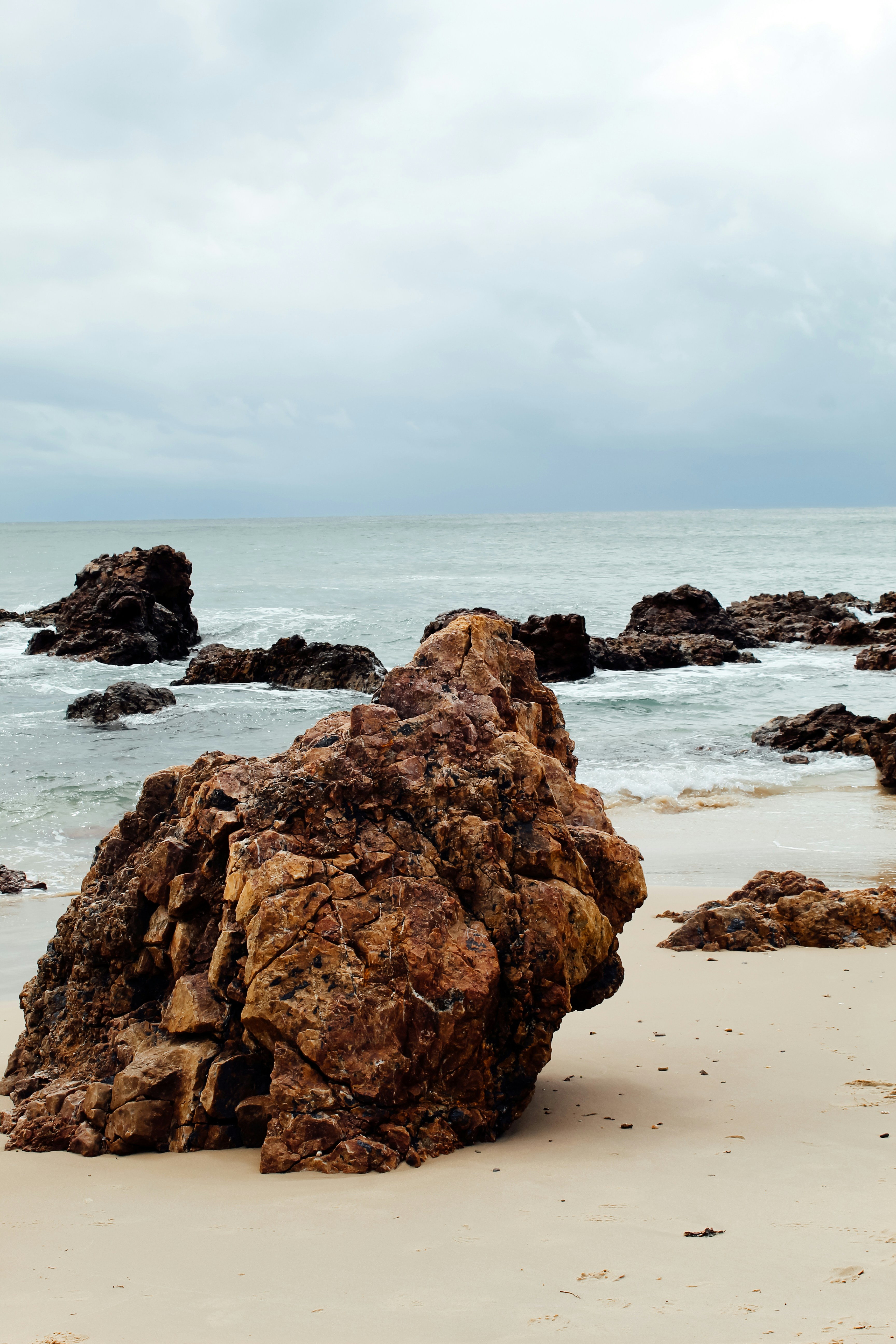 Un gros rocher posé au sommet d’une plage de sable photo – Image ...