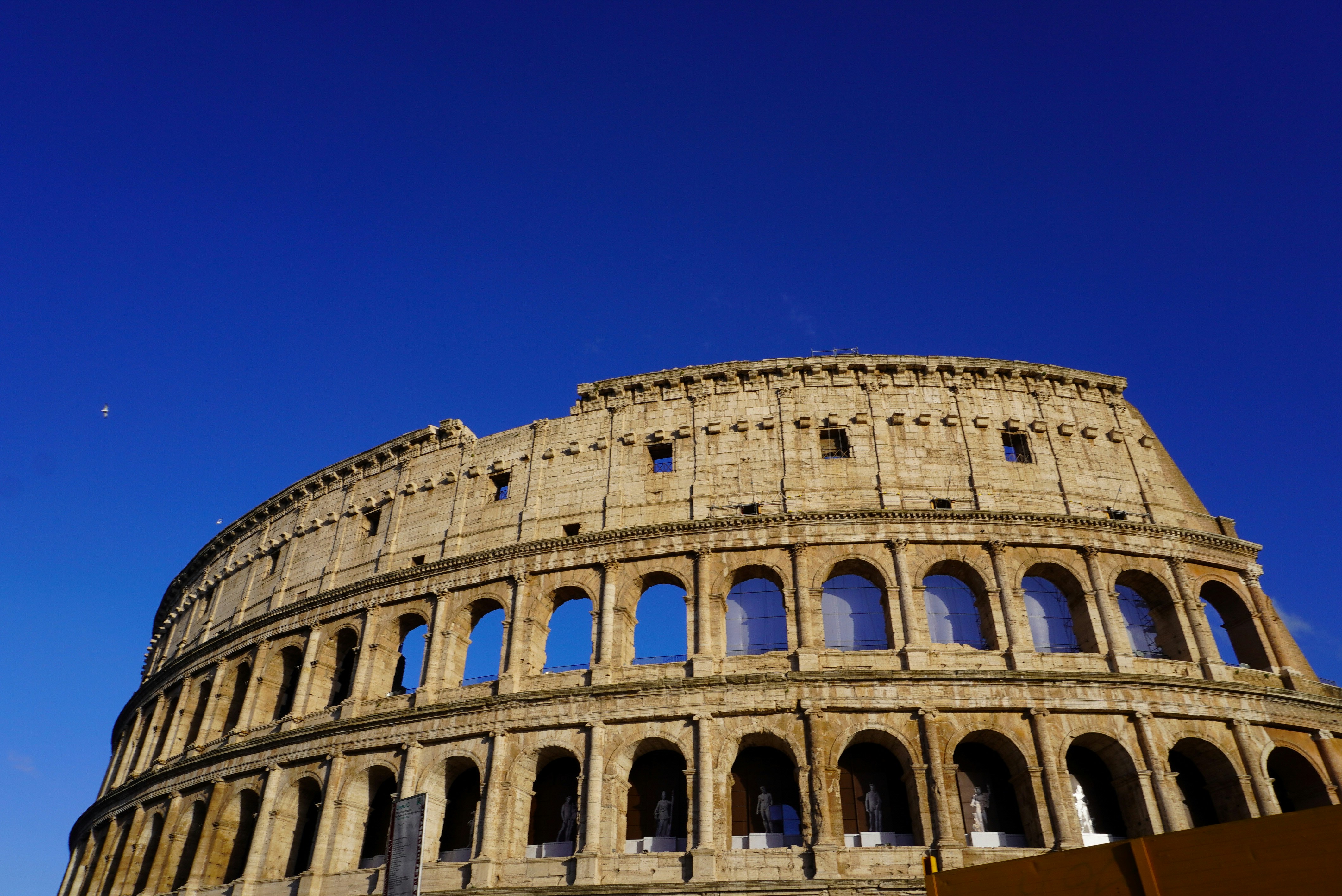 The Colosseum's arches and stone facade contrast against a deep blue sky.