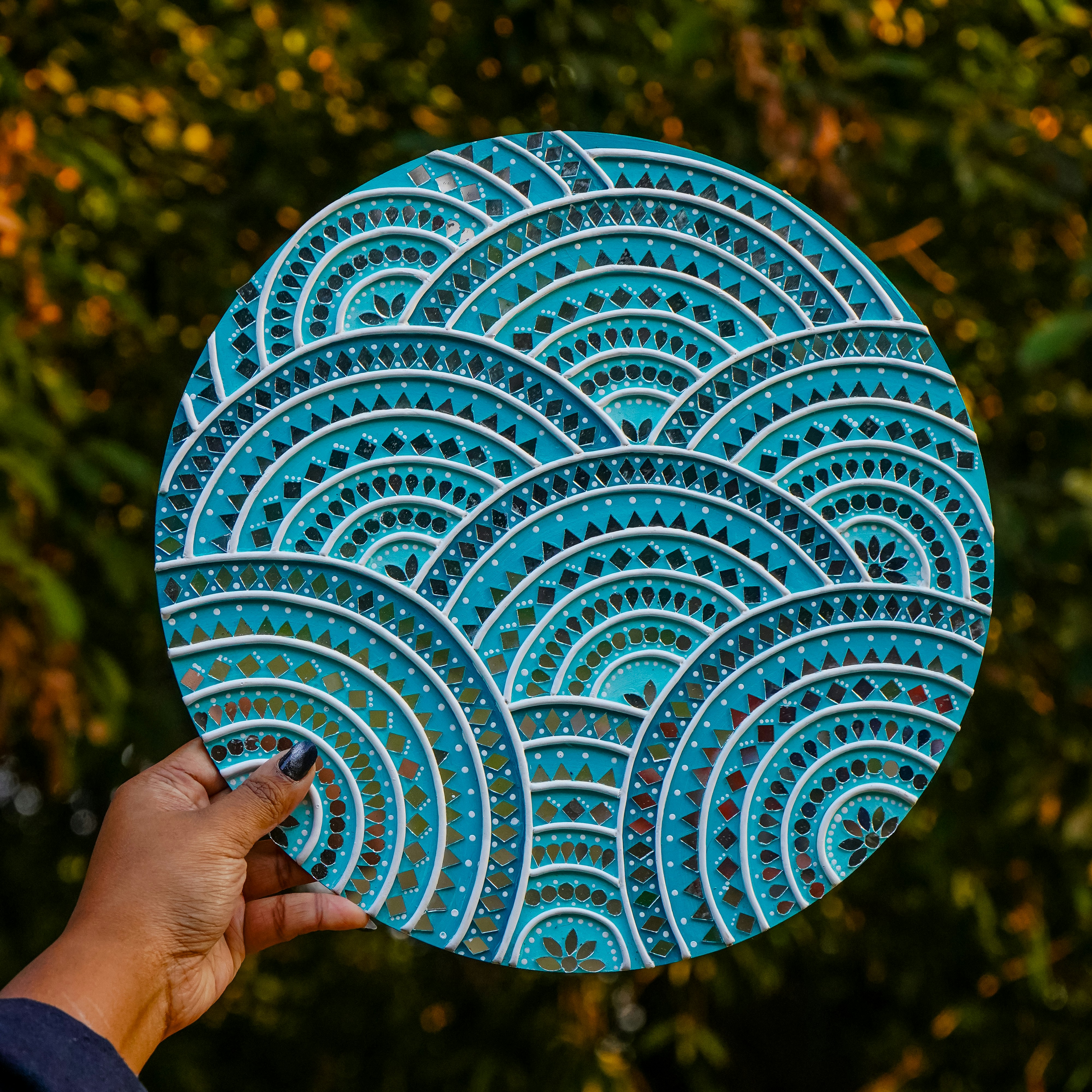 Blue Rhythms: Circular Tile Plate Held Against Autumn Backdrop
