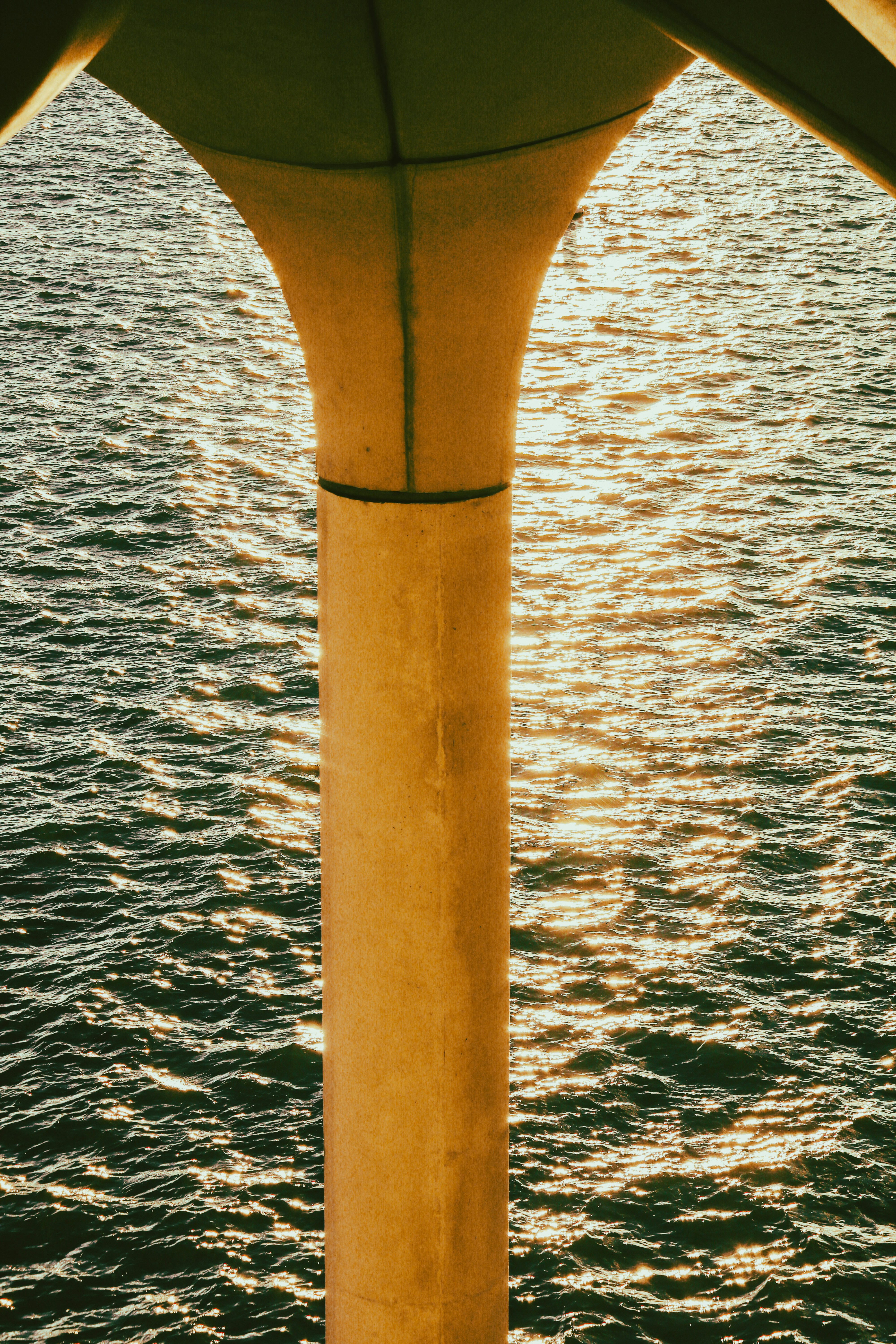 Bridge Pillar in Golden Hour: A Pier Framed by Rippling Water