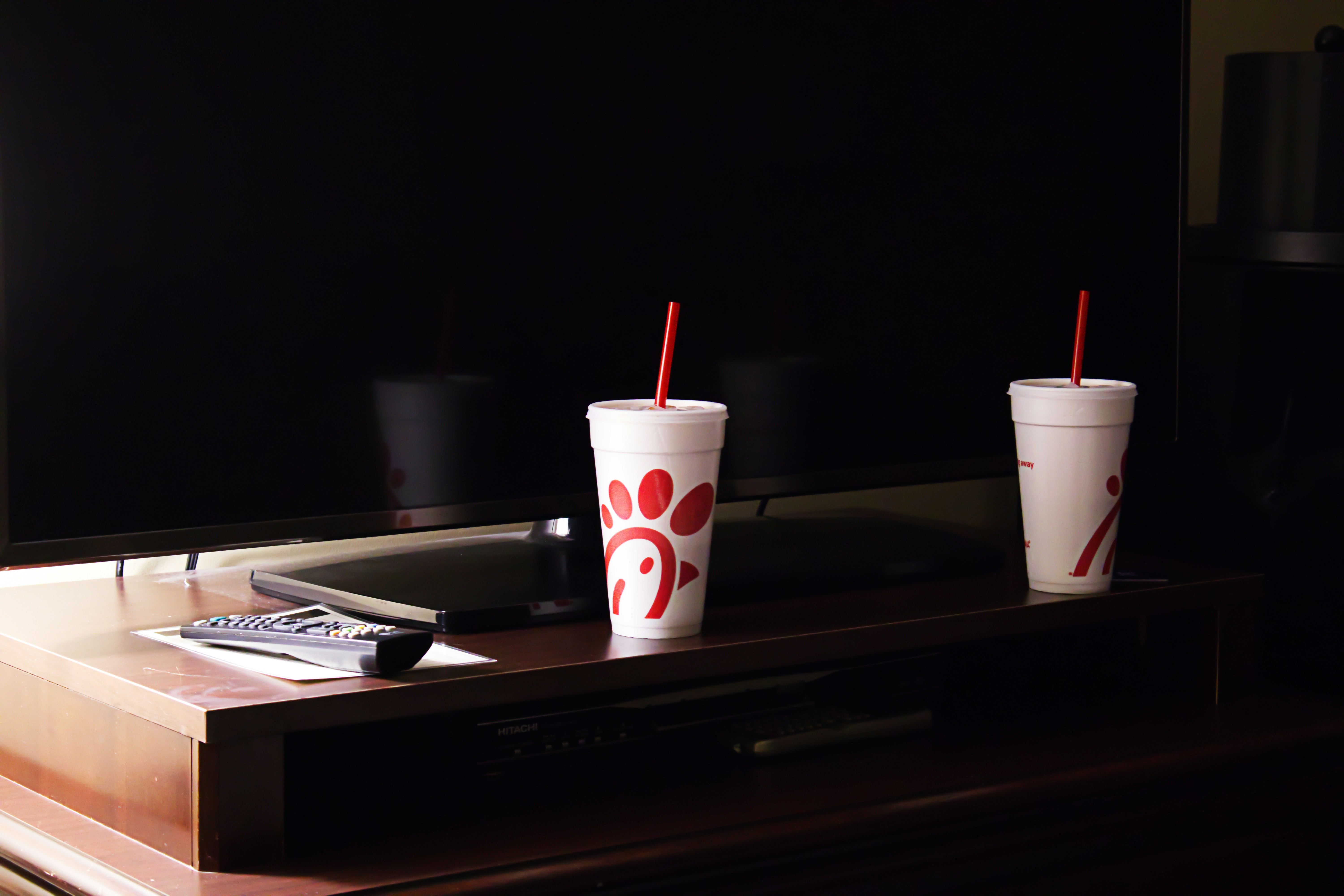 Quiet Glow on the Shelf: Two Chick-fil-A Cups Under Dim TV Light