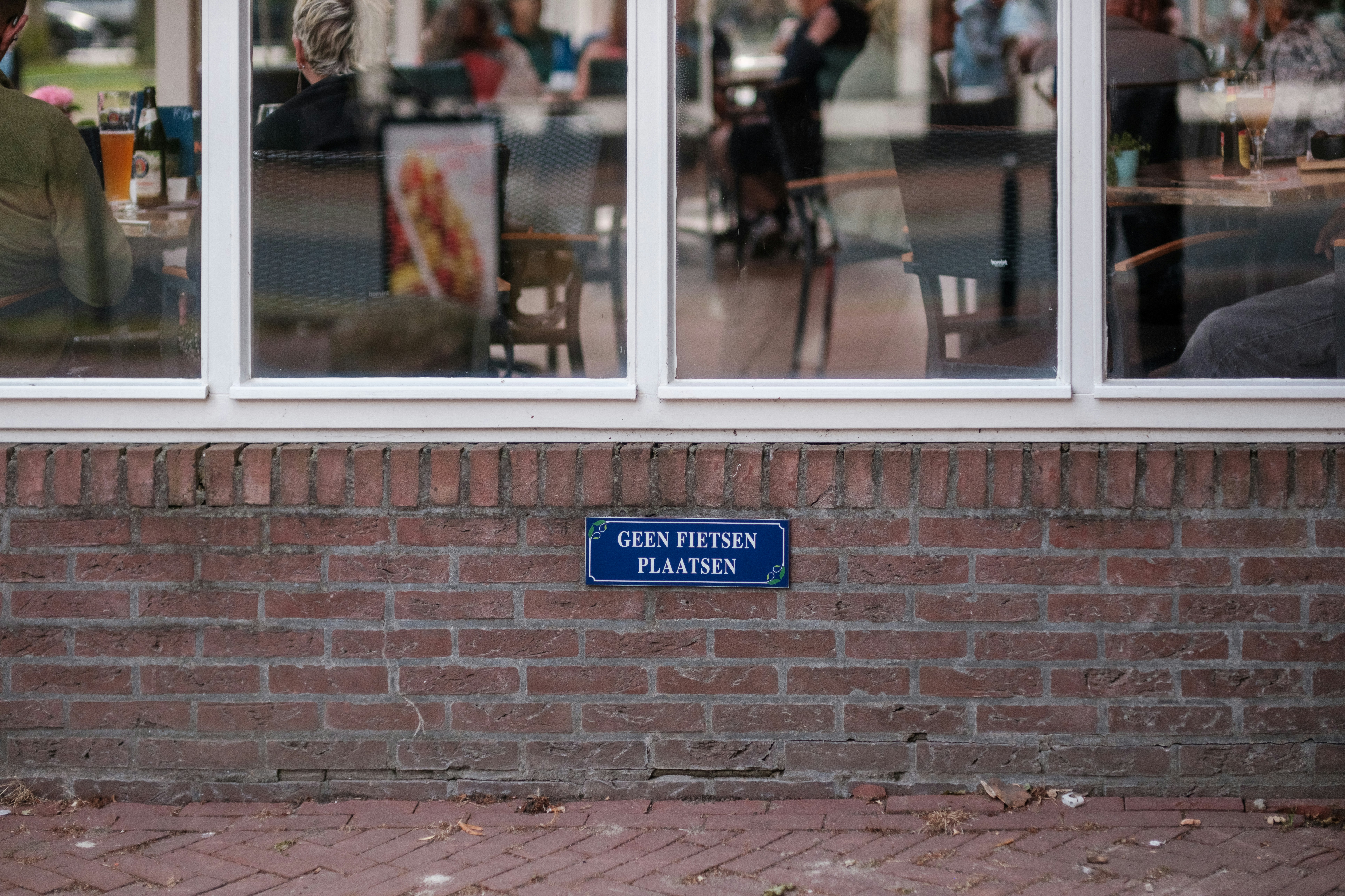 Brick-Walled Café Window Scene with a Central Blue Plaque