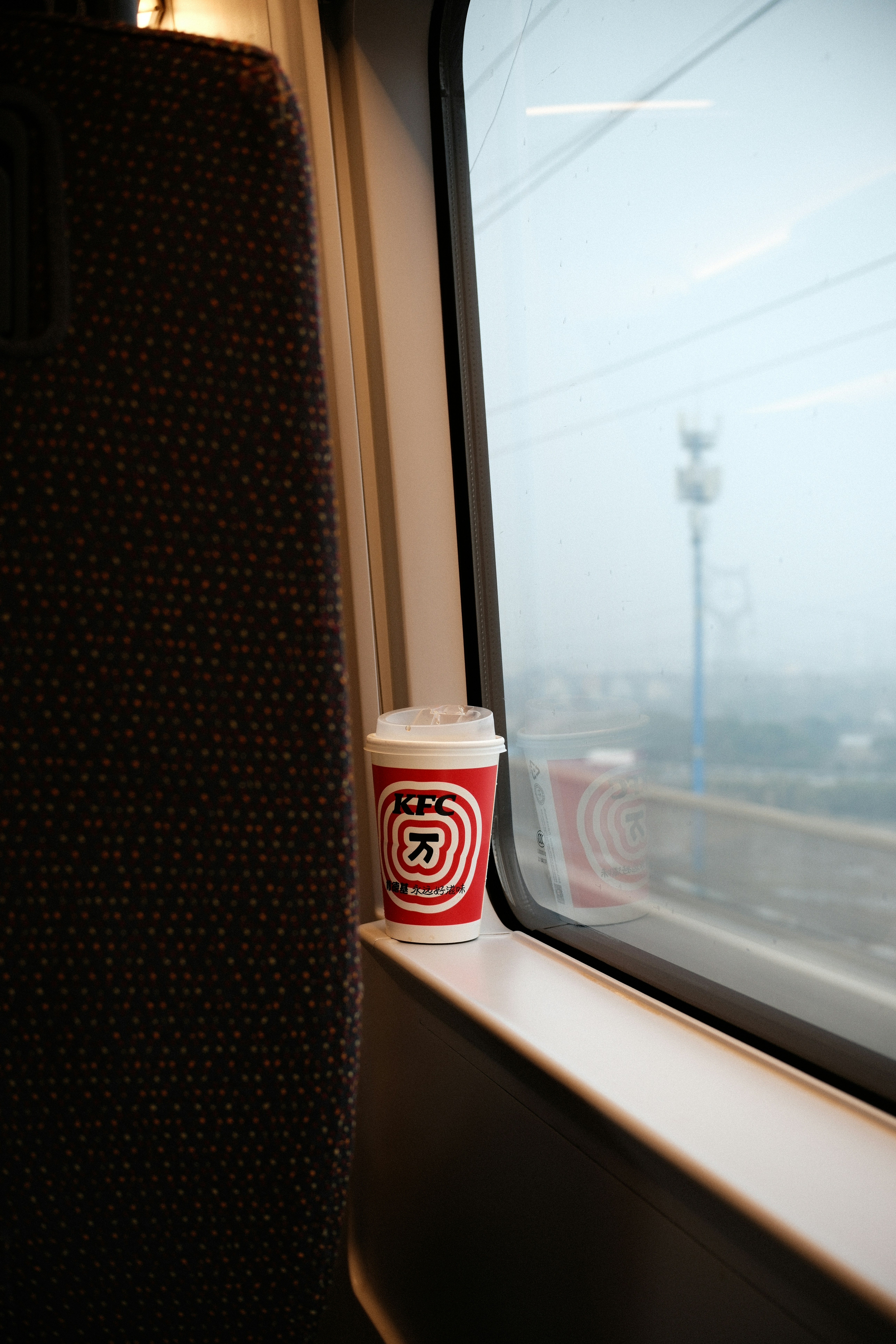 Red Cup Perch: A KFC Cup on a Train Window in Transit