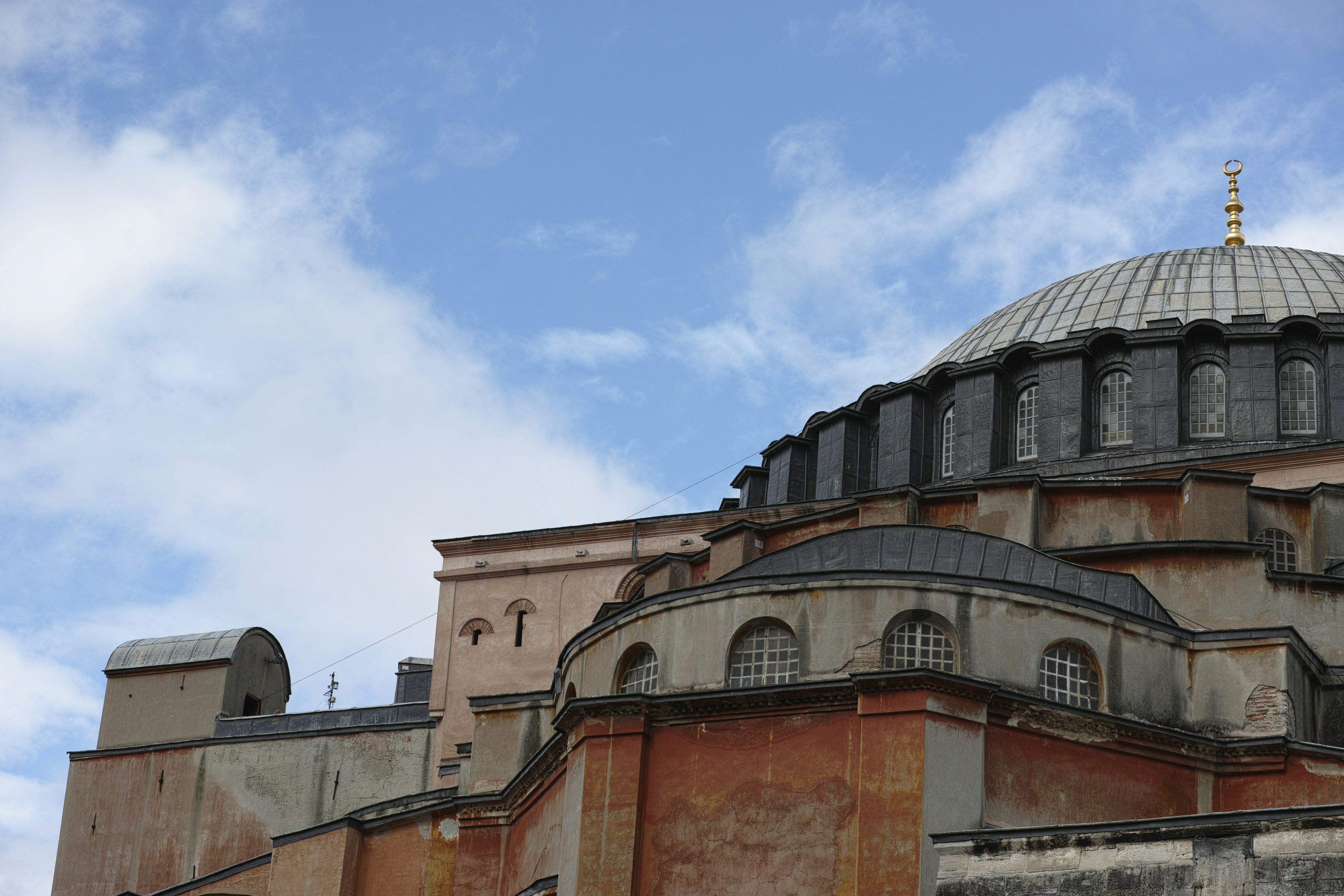 Intricate facade and dome of Hagia Sophia under a partly cloudy sky.