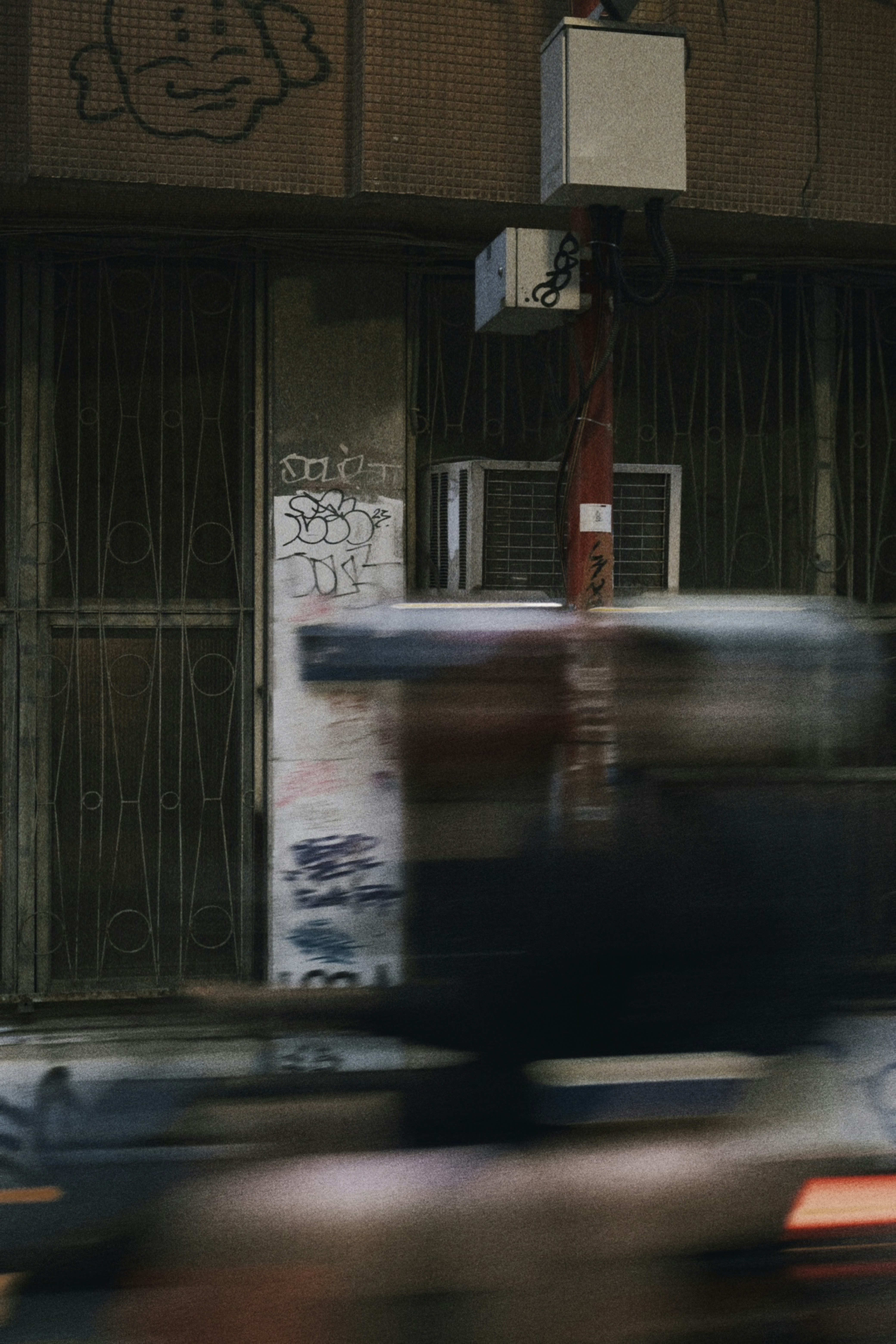 A blurred motorcycle speeds past a graffiti-covered wall, capturing the essence of urban movement and energy.