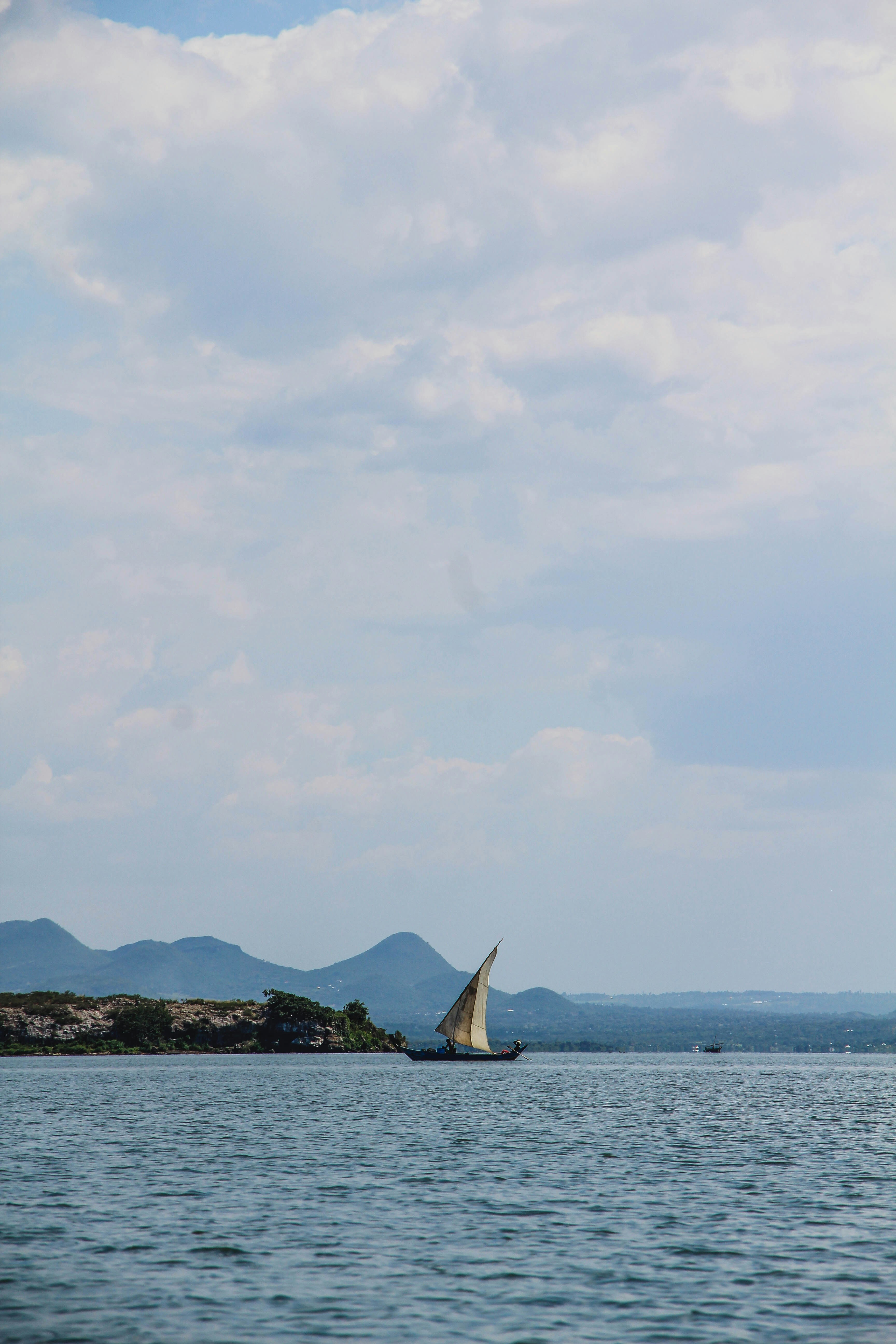 Lone Sail Slicing the Quiet Azure by a Coastal Ridge