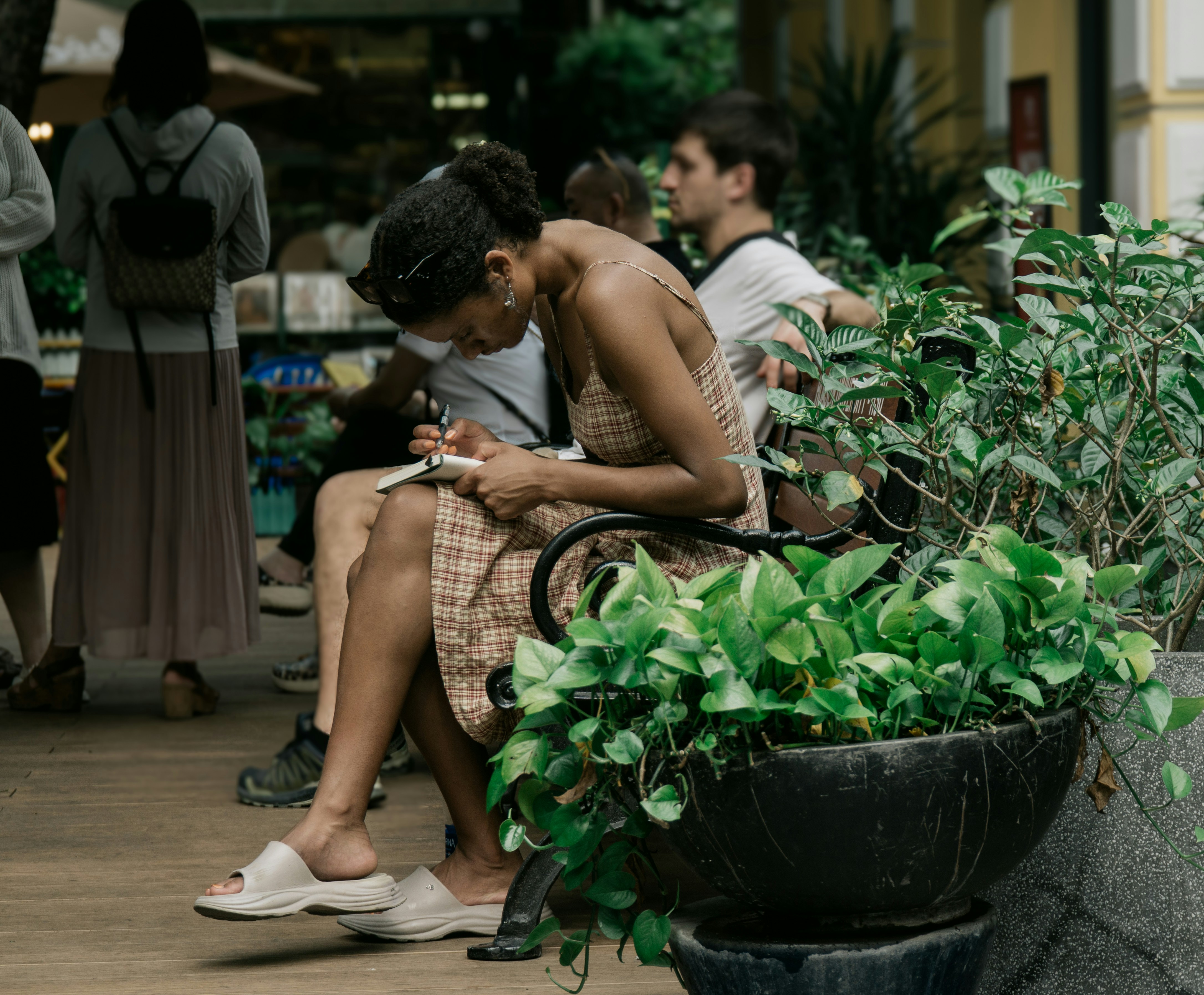 Quiet Moment on Campus: A Woman in a Checkered Dress Immersed in Her Phone