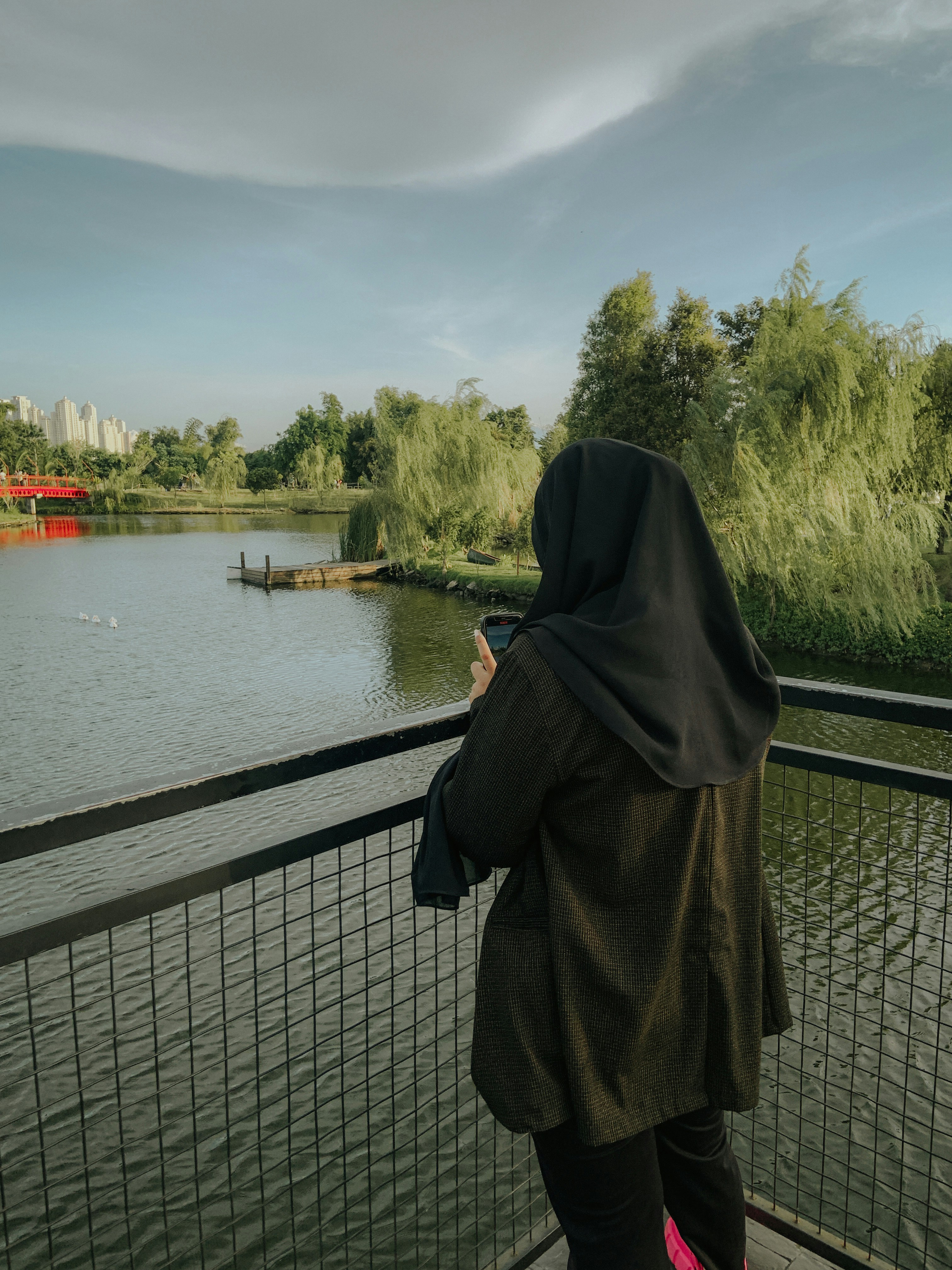 A woman standing on a bridge looking at the water photo – Free Woman ...