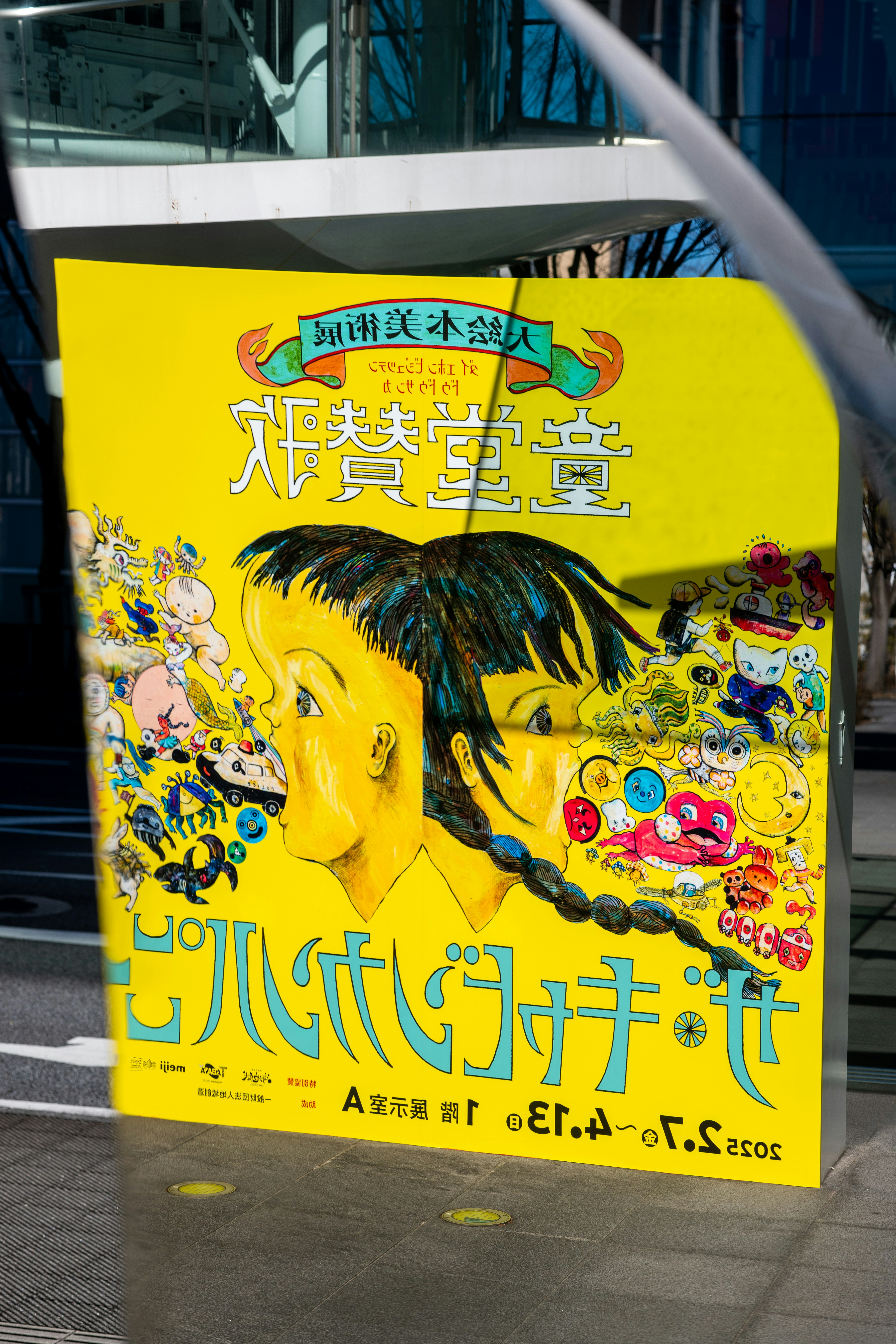 Vibrant mural featuring two faces sharing colorful thoughts and whimsical characters, set against a bright yellow backdrop.