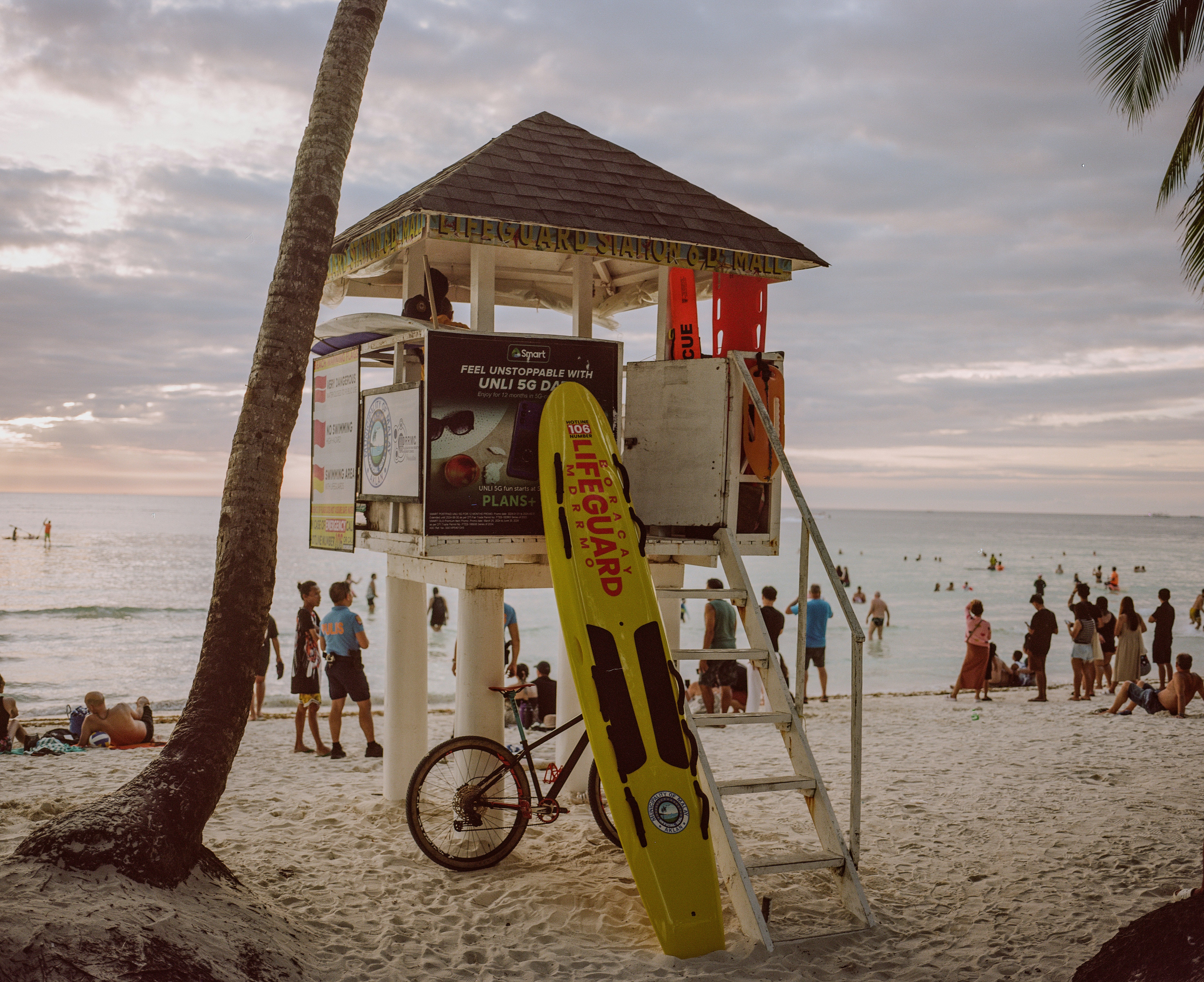 A lifeguard stand on the beach with a surfboard leaning against it ...