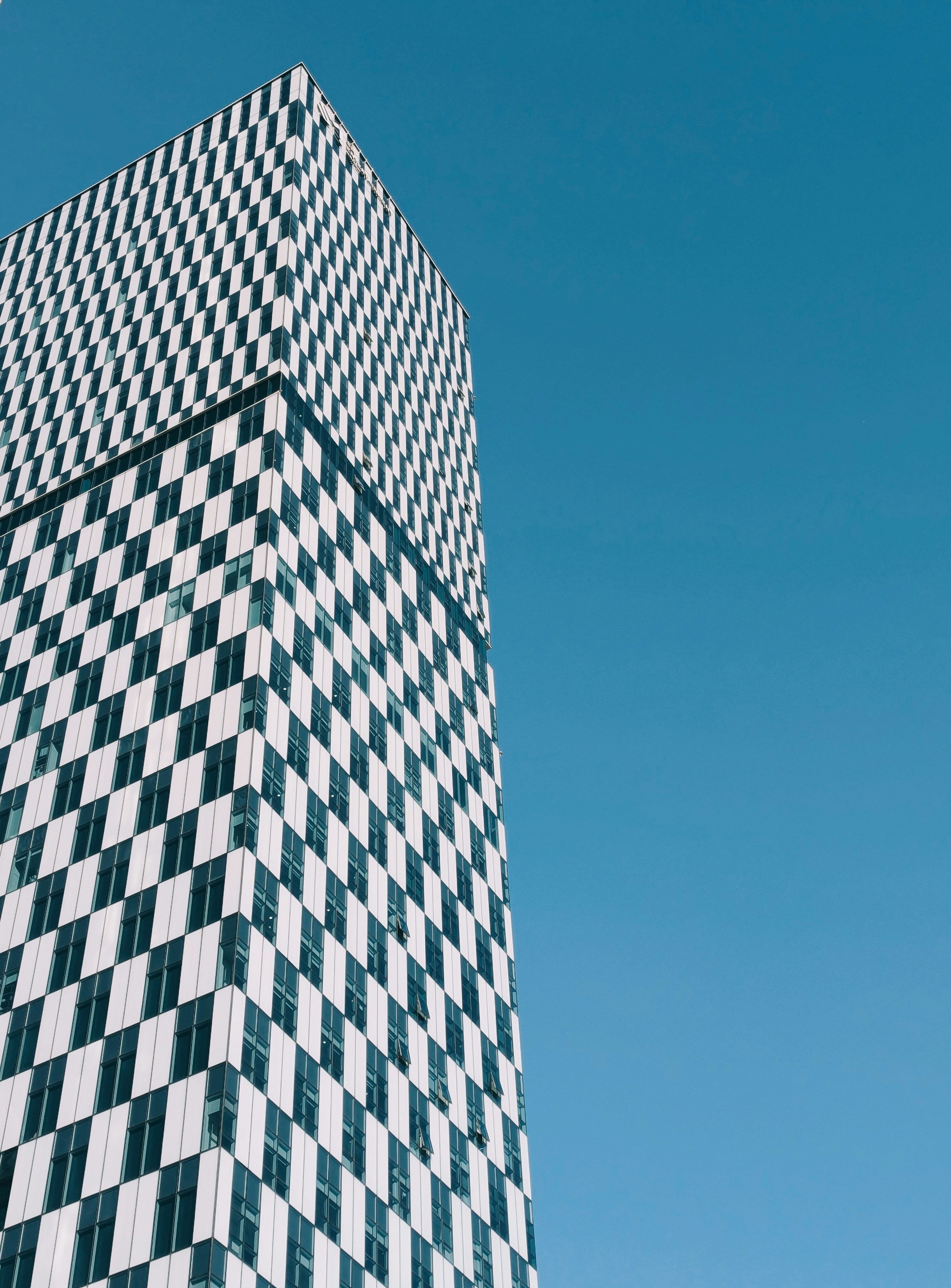 Edge of the Sky: A Checkerboard Tower Rising Against a Clear Blue